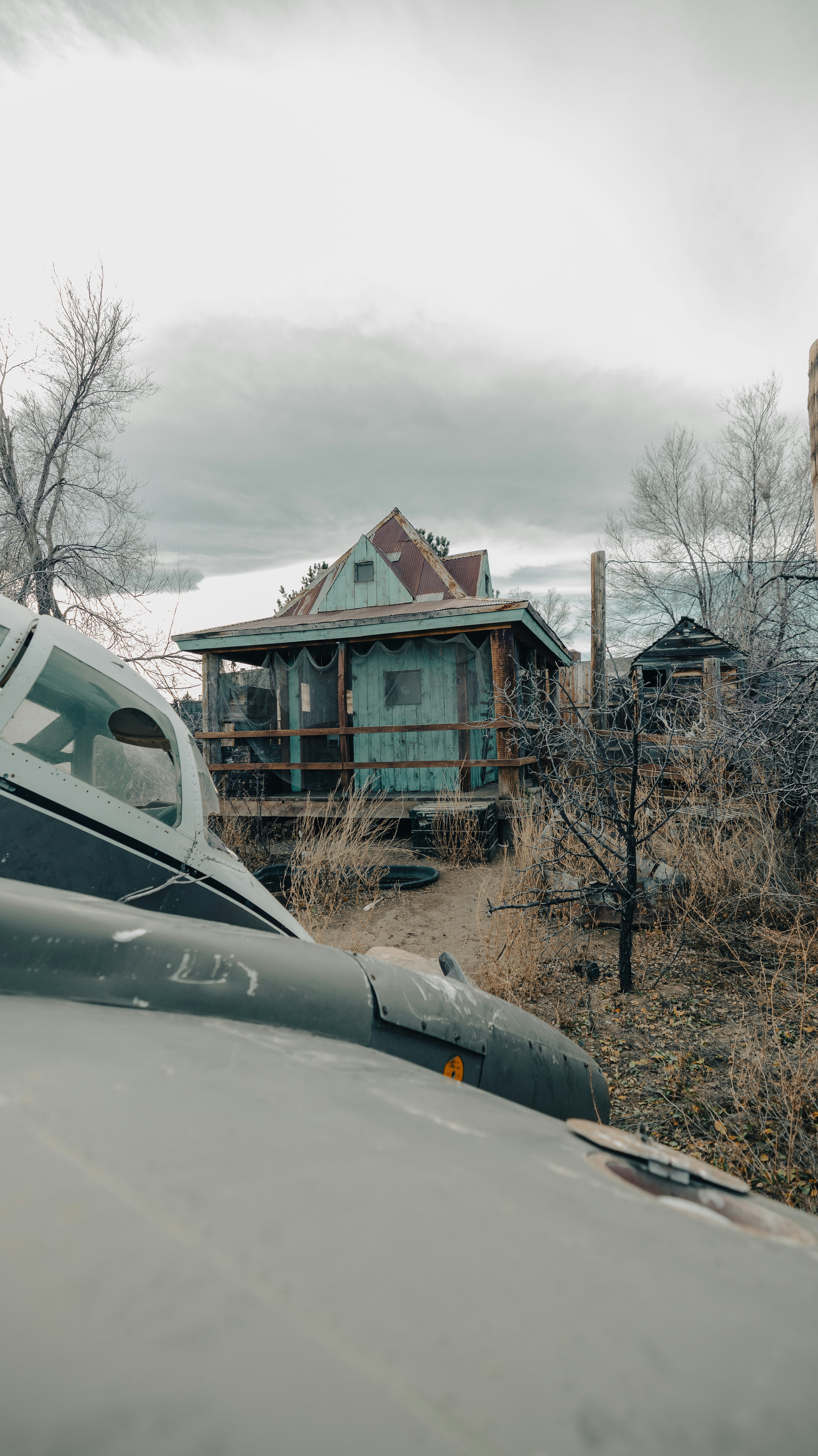 Rust and Road: An Abandoned House Framed by a Weathered Aircraft