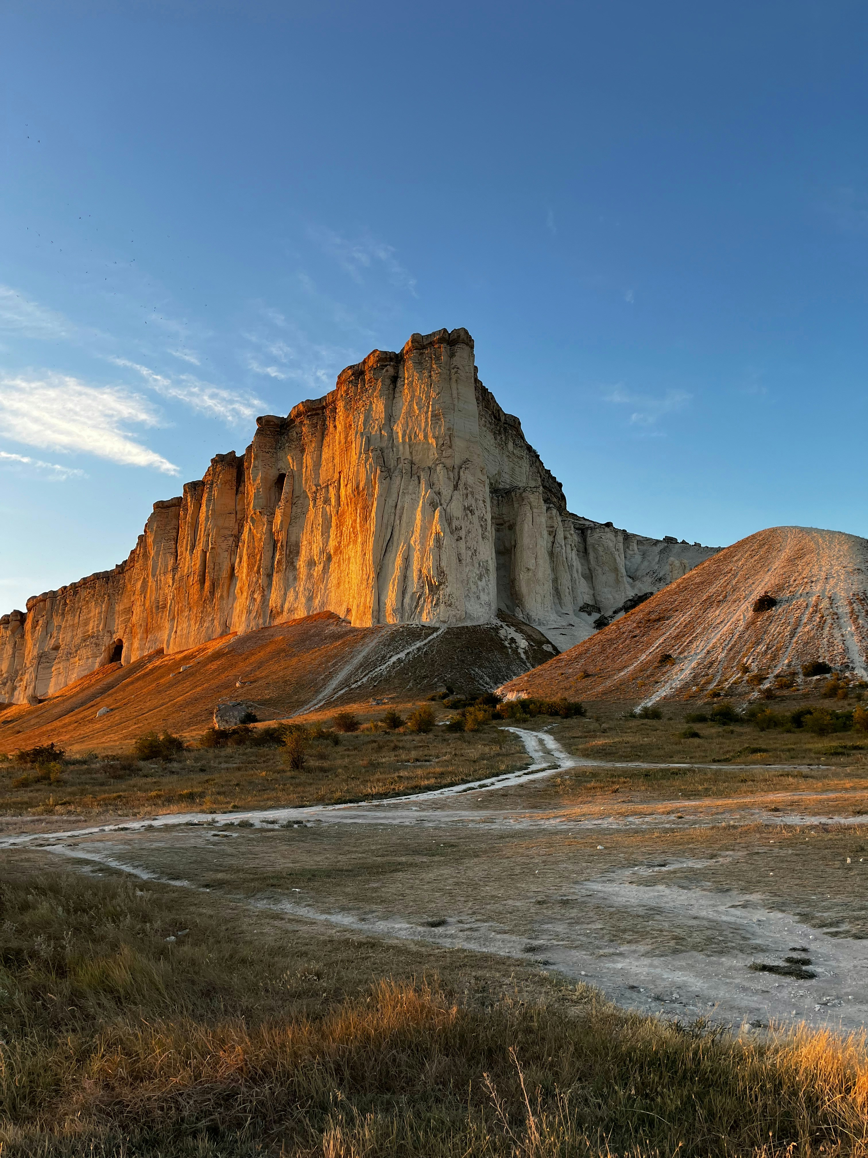 Heroic cliff face bathed in sunset light on a desert hillside