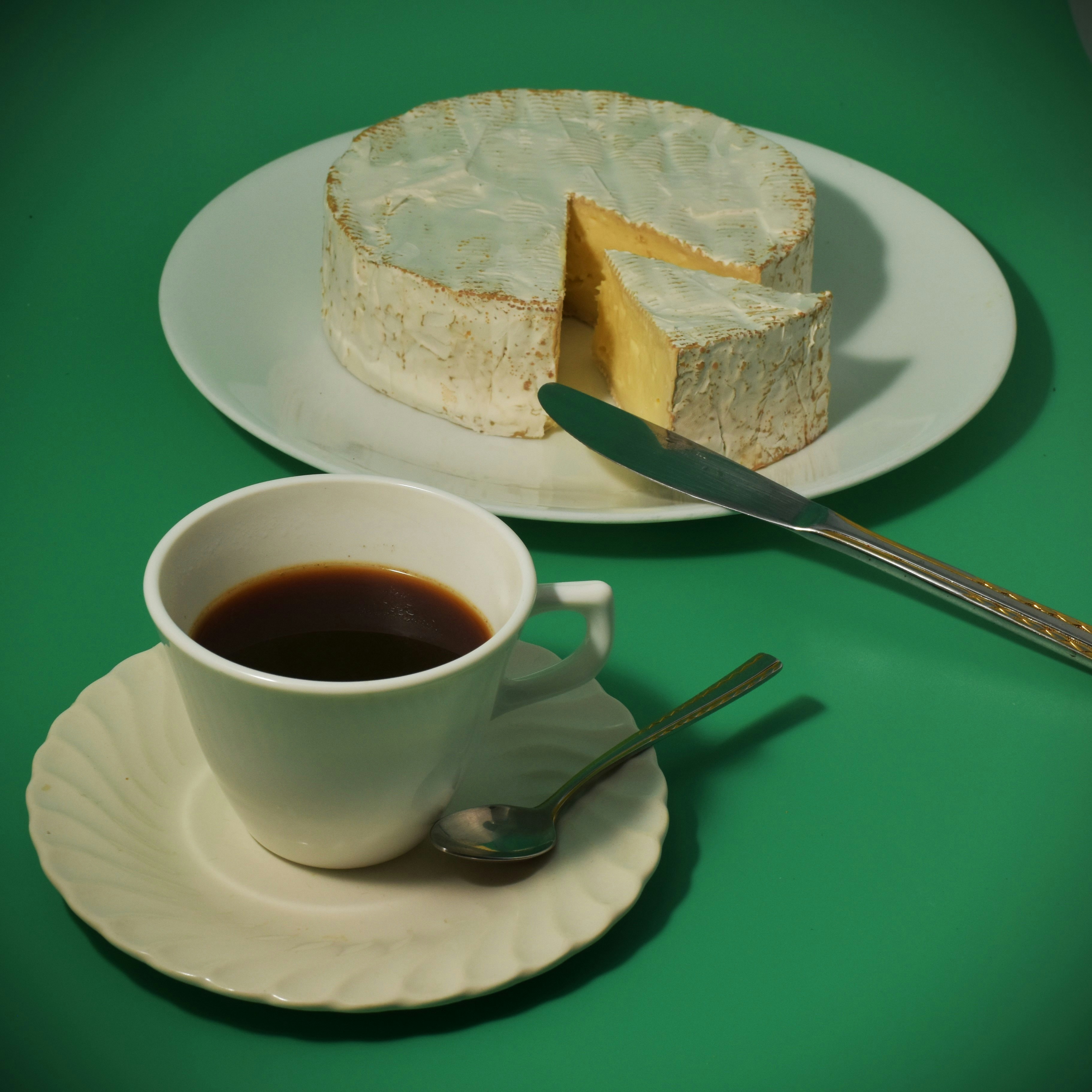 A slice of citrusy cheesecake near a cup of dark coffee