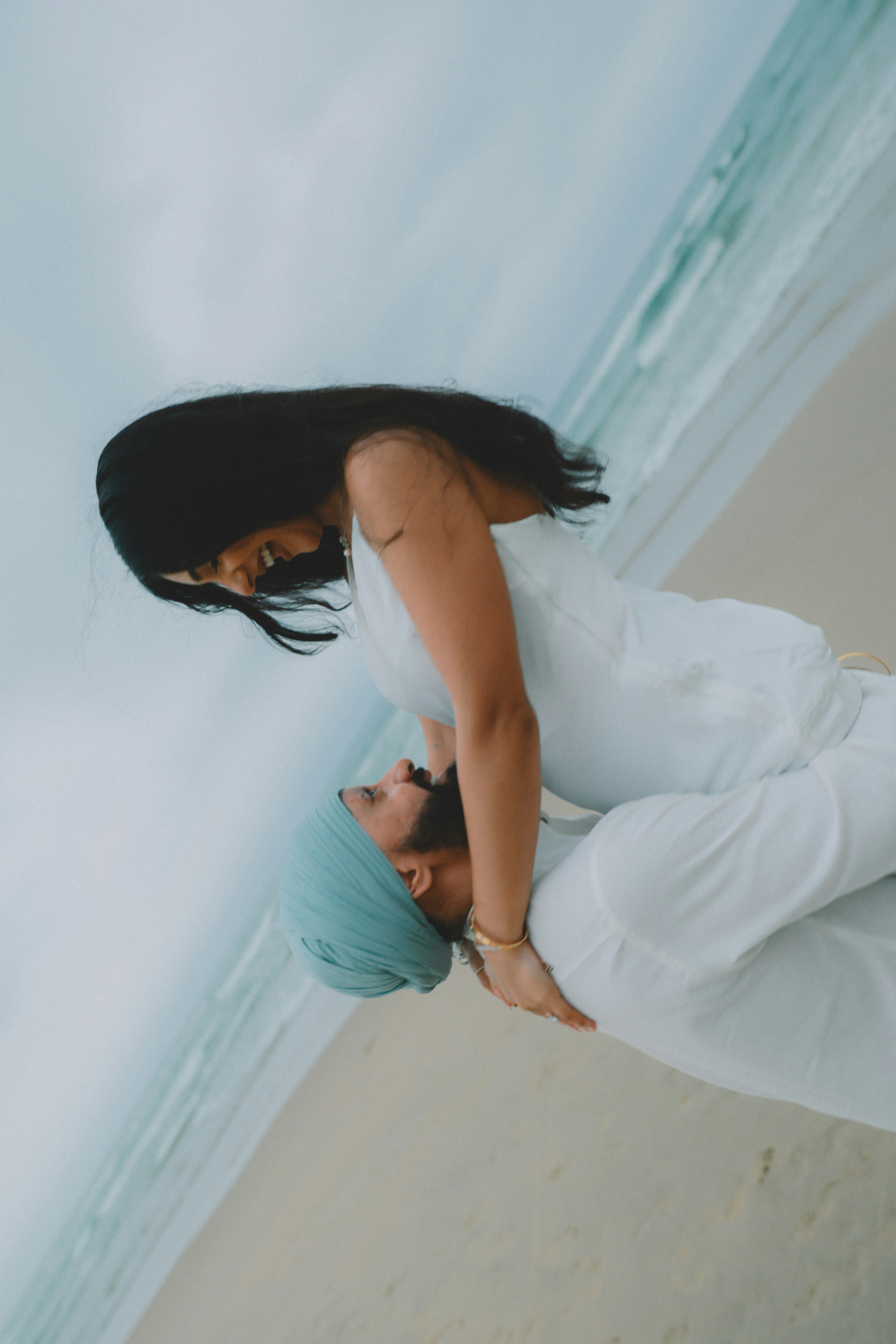 Bride and groom embrace on a windswept beach at seafoam sunset