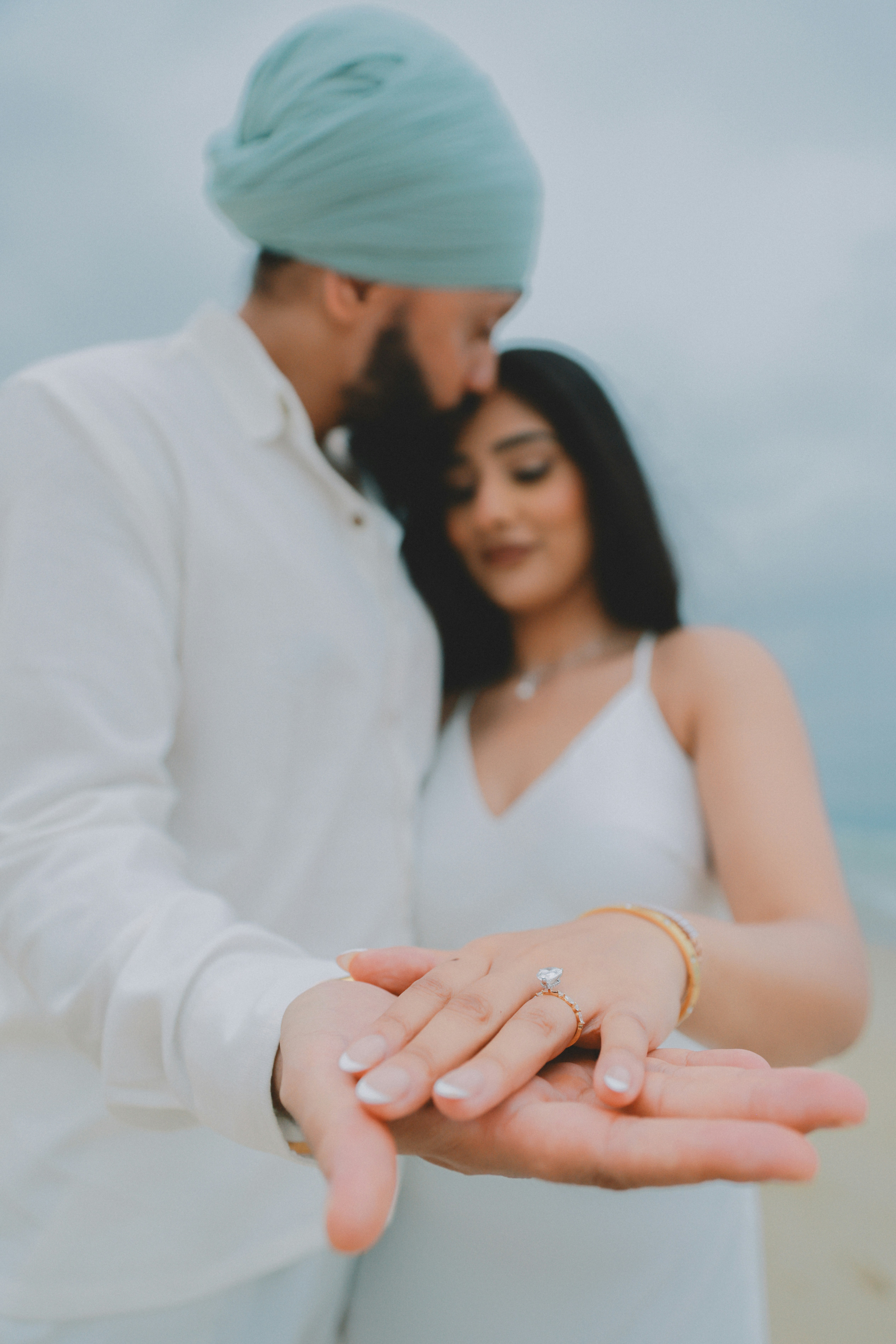 Couple showing engagement ring on beach