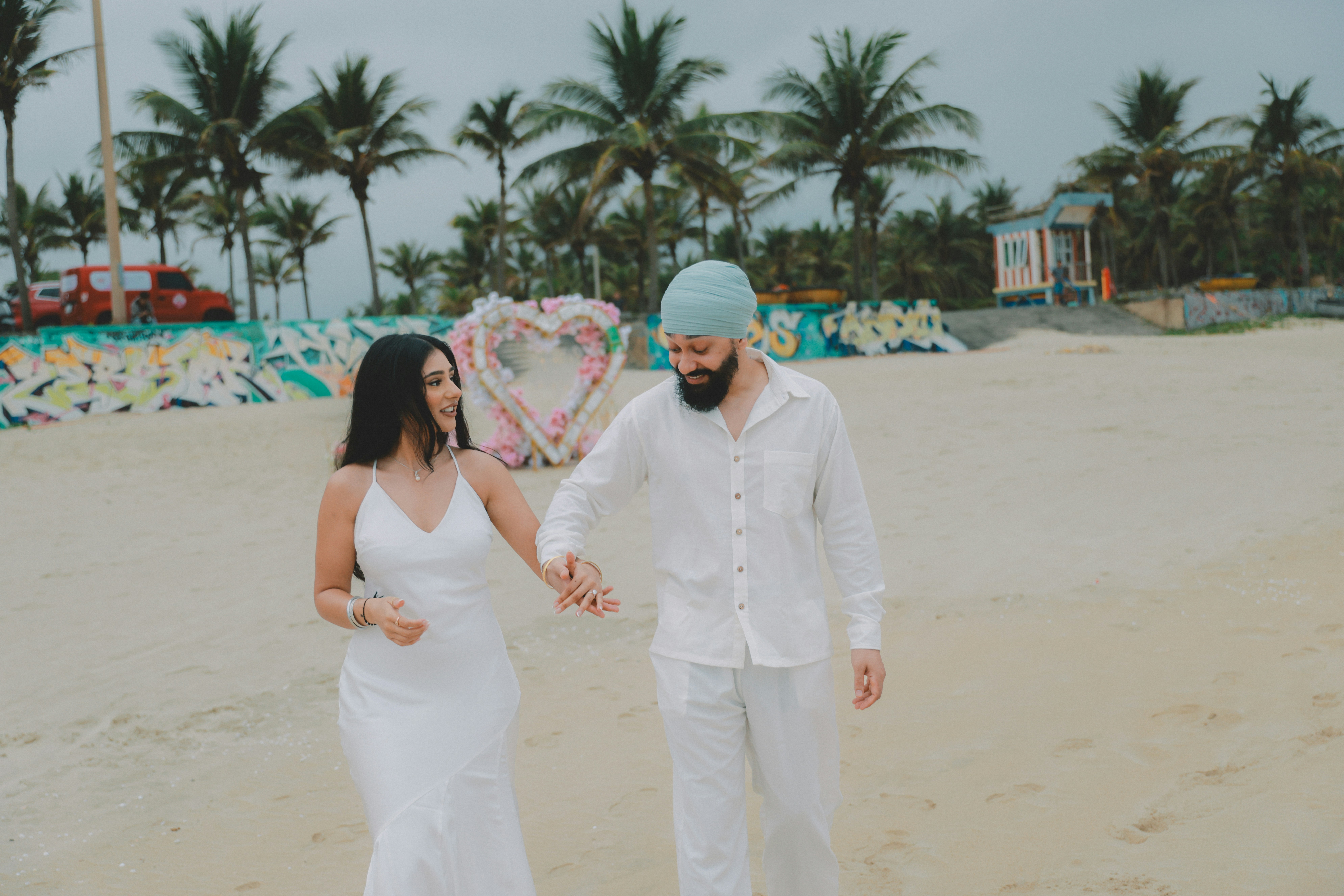 Coastal vows: a couple strolls hand in hand along a sunlit beach