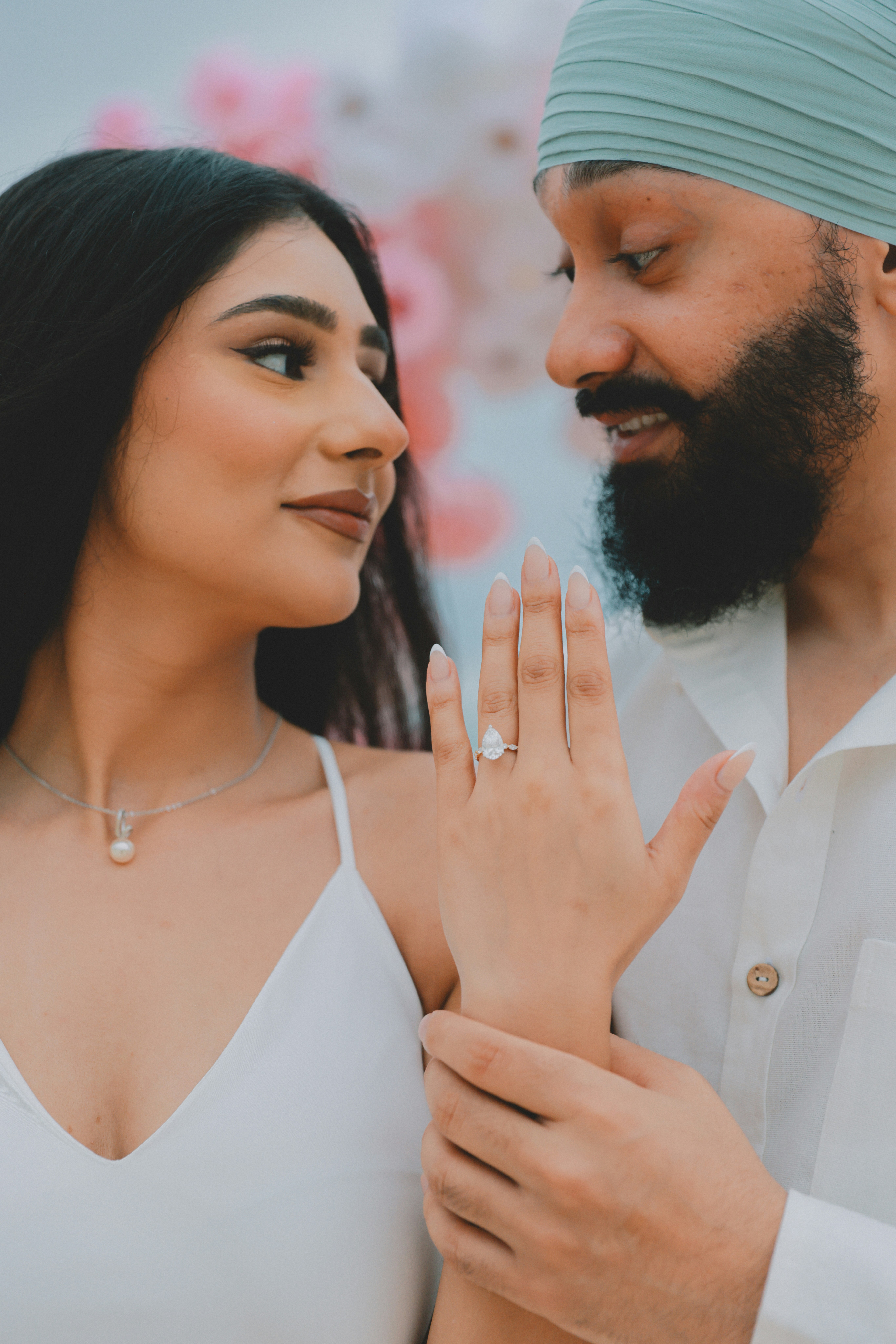 Couple looking at engagement ring with pink hearts