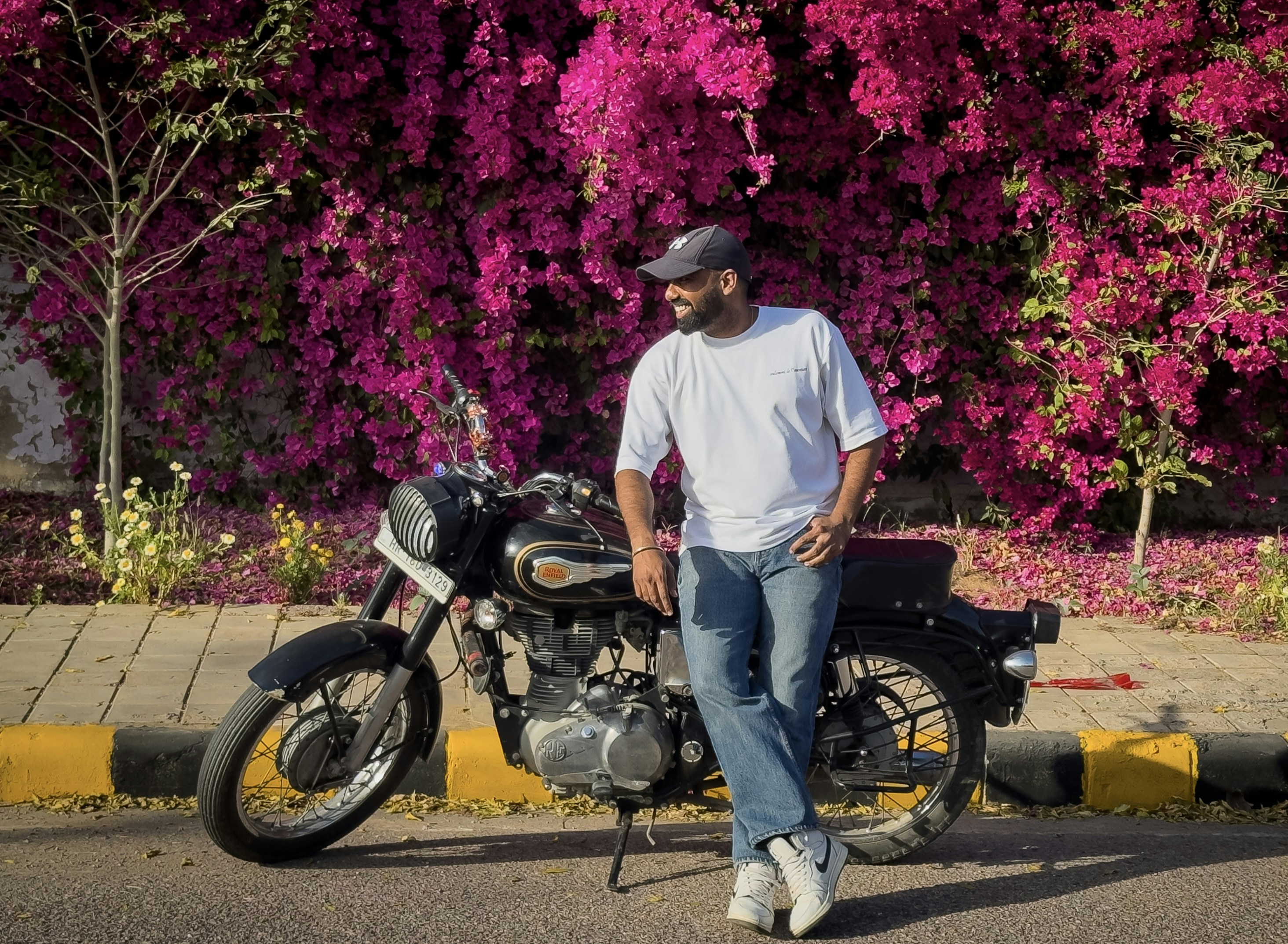 Man Leans on Classic Motorcycle Under Vivid Bougainvillea