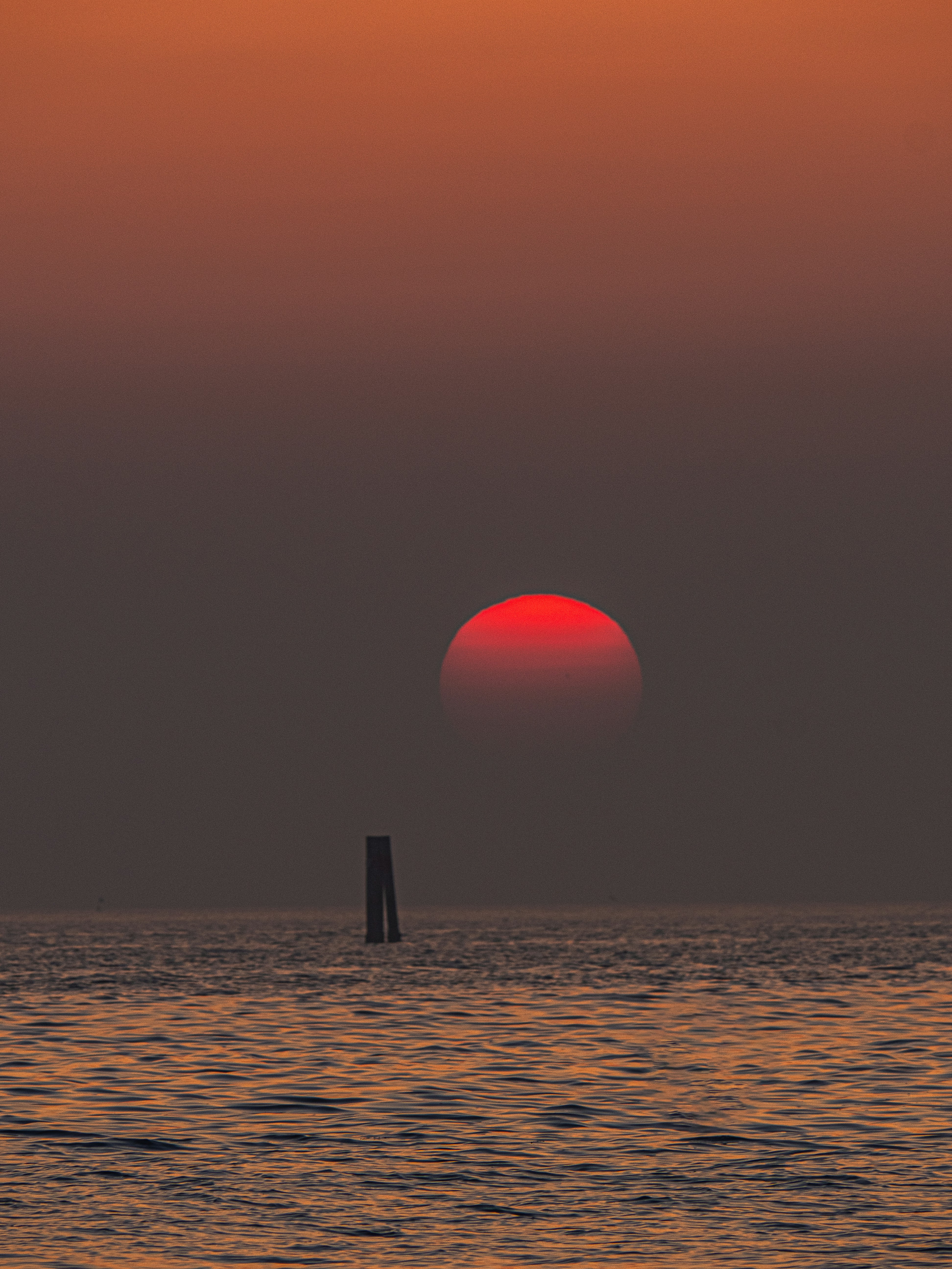Red Sun on Distant Horizon Over Quiet Seas