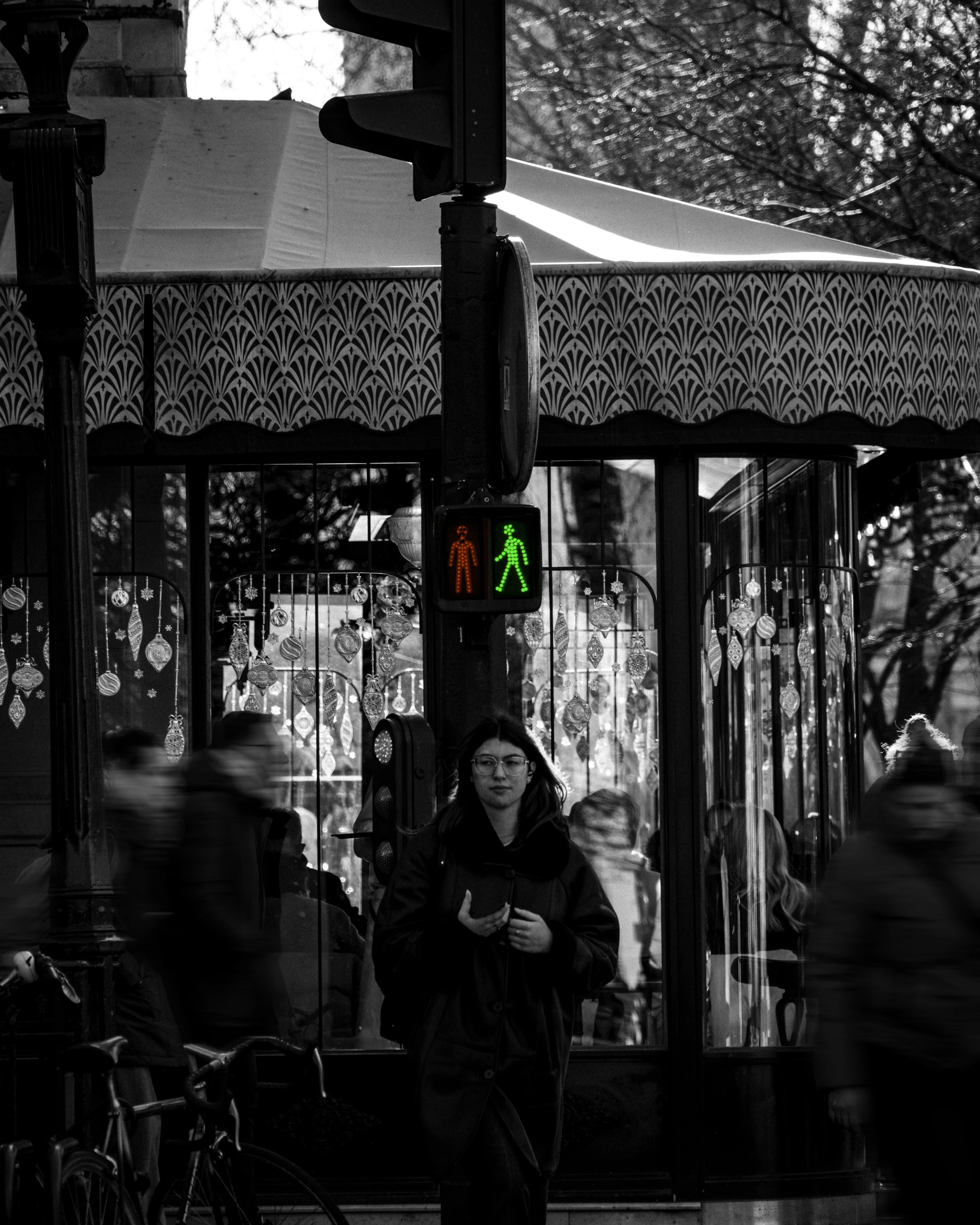Crosswalk Quiet: A Woman Waiting Under a Dotted Canopy