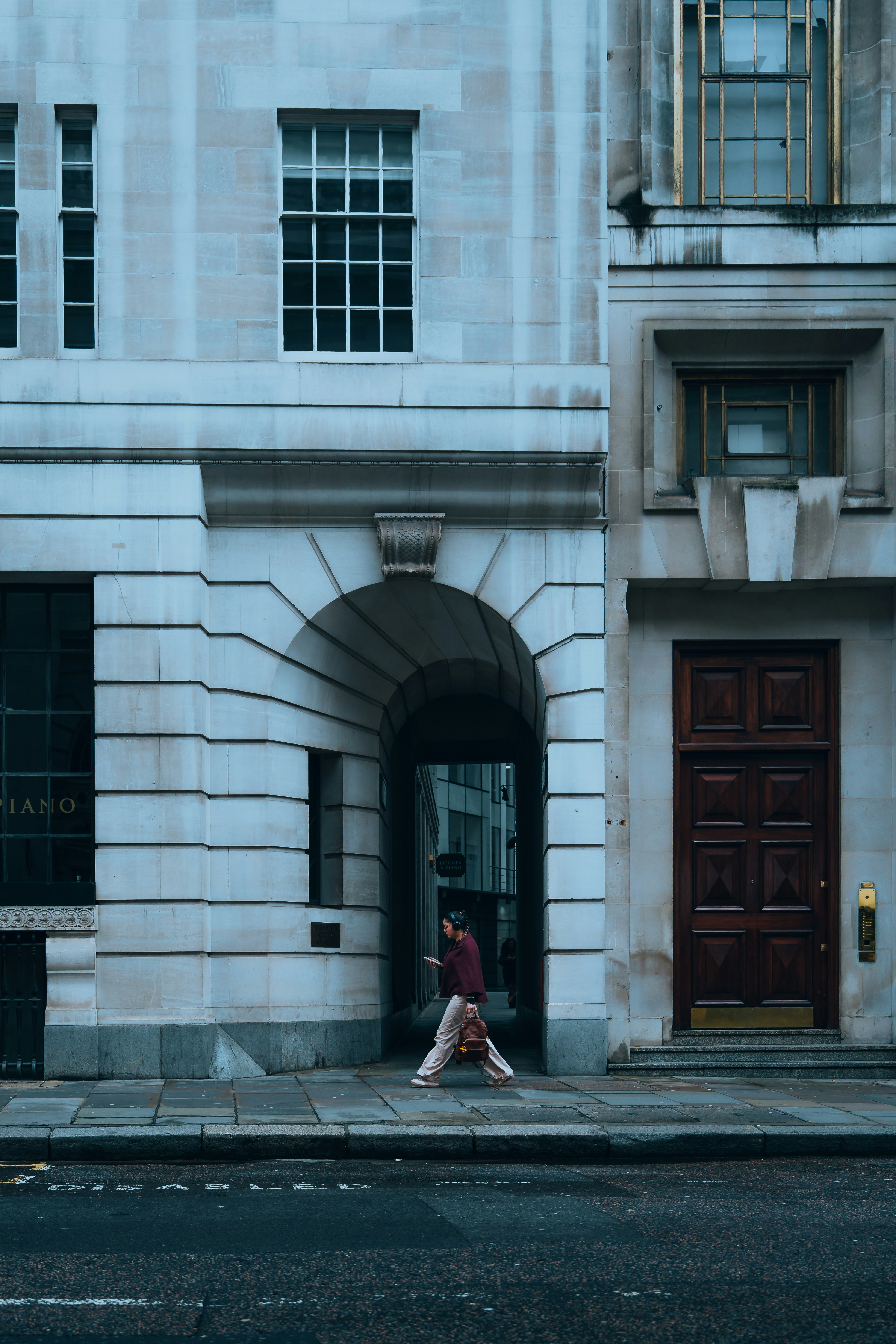 Pedestrian in a City Archway: The Quiet Moment Between Facades