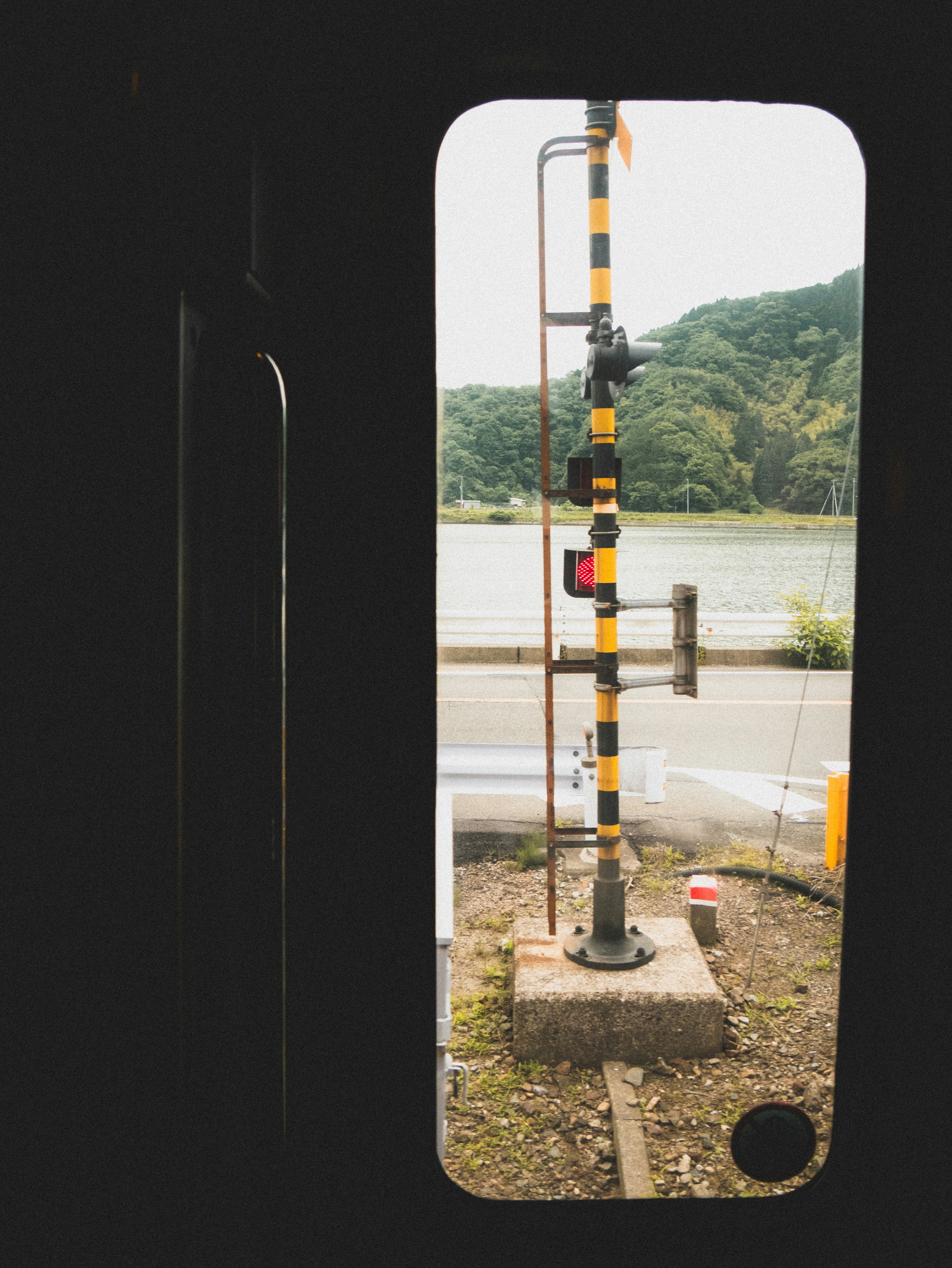 Through the Cabin Window: A Riverside Signal Post Framed by Steel and Glass