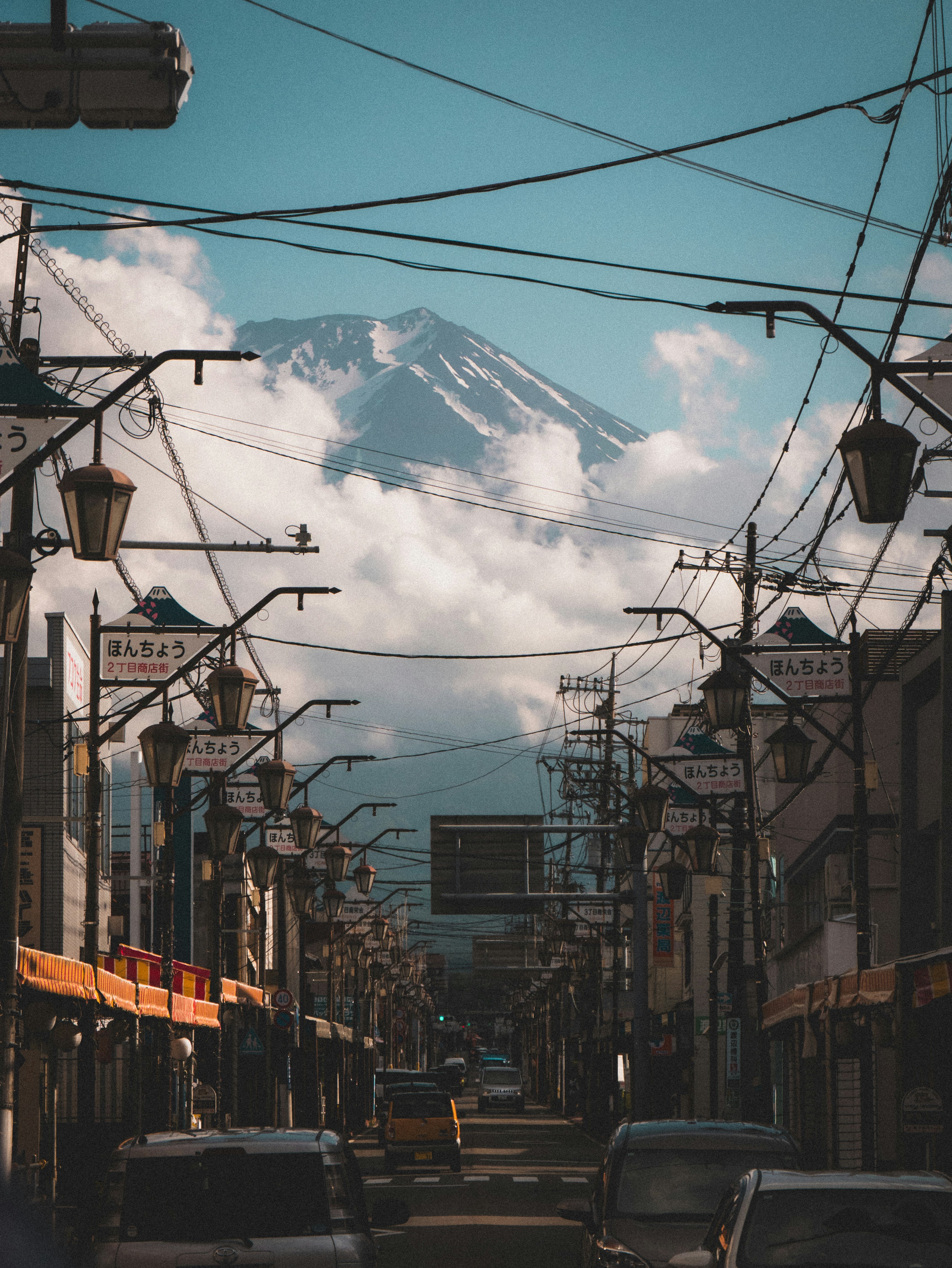 Street beneath a looming mountain: urban wires frame a distant peak