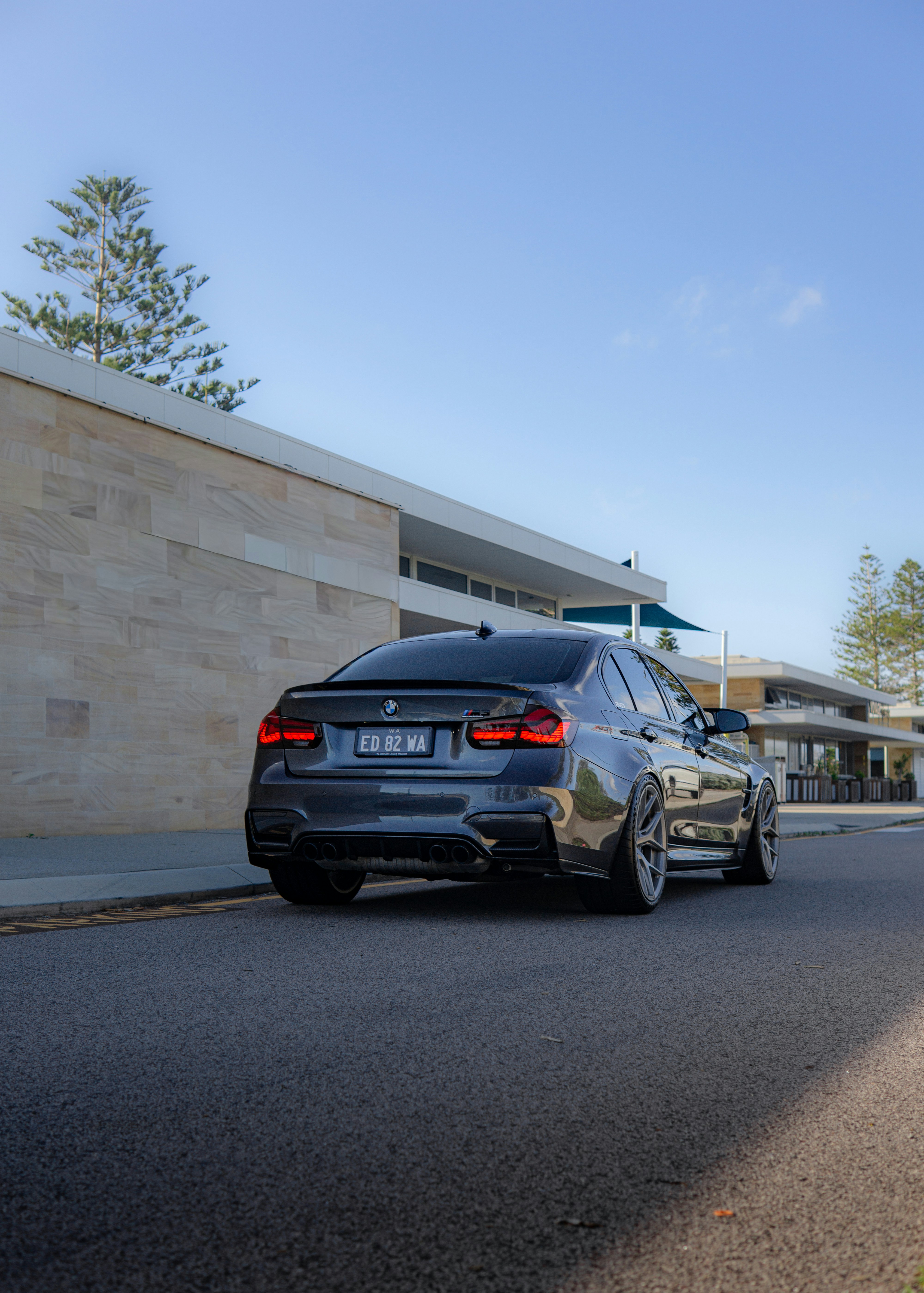 Low-Angle Retreat: A Charcoal BMW Stretched Along a Modern Campus Road