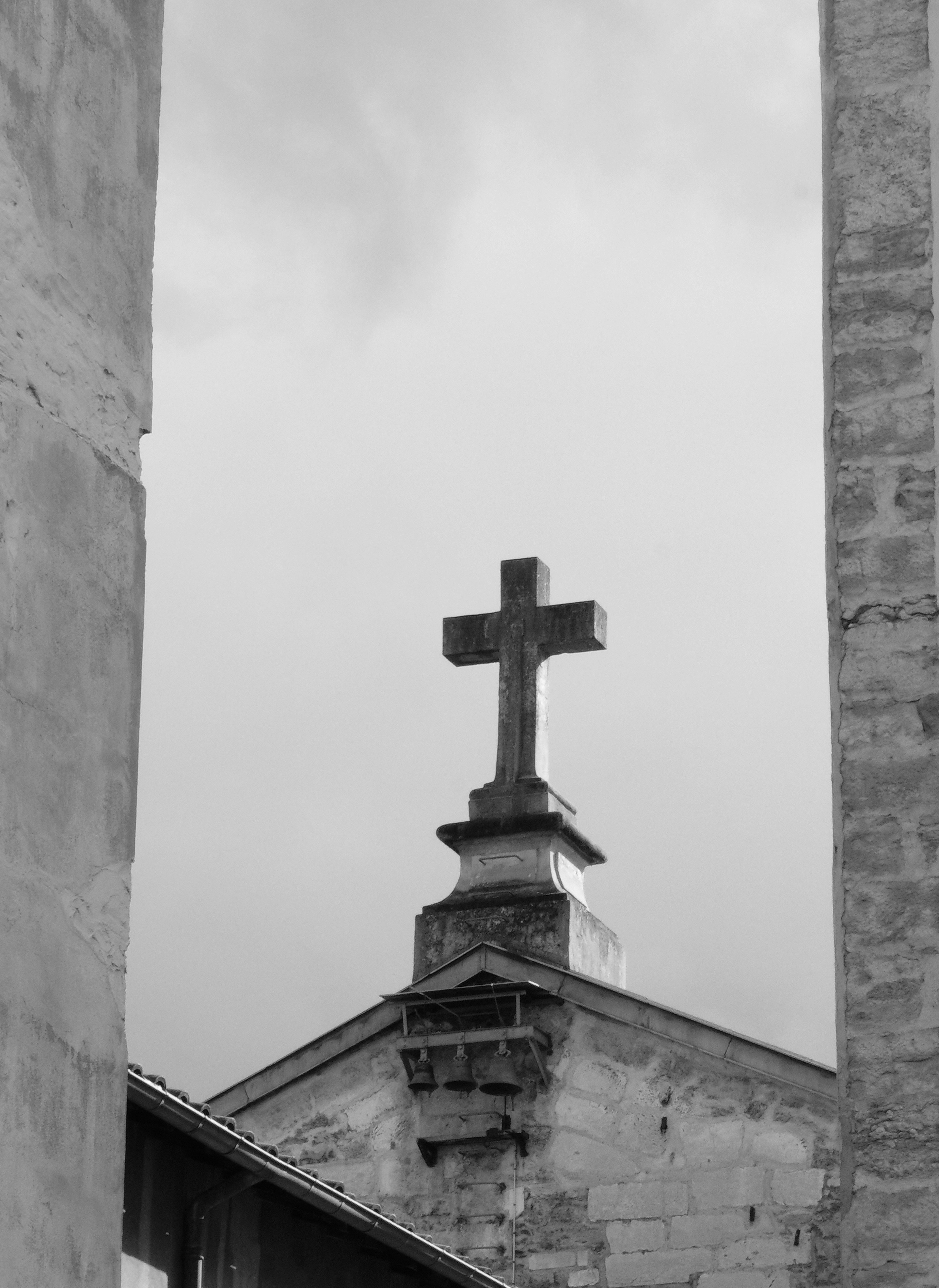 Cross atop a quiet church roof framed by weathered stone