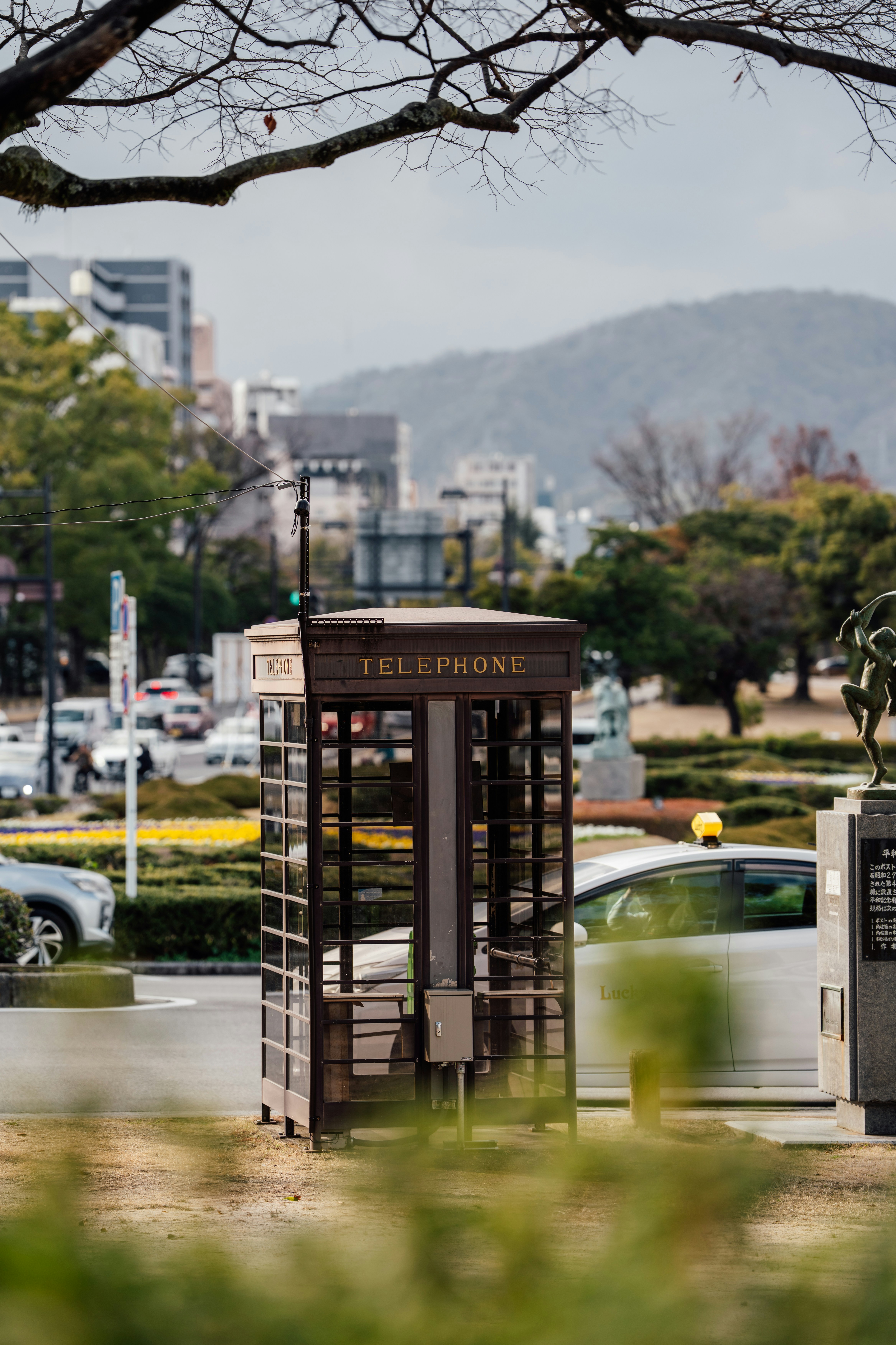 Vintage Kiosk in Transit: A Telephone Box Framed by City Life