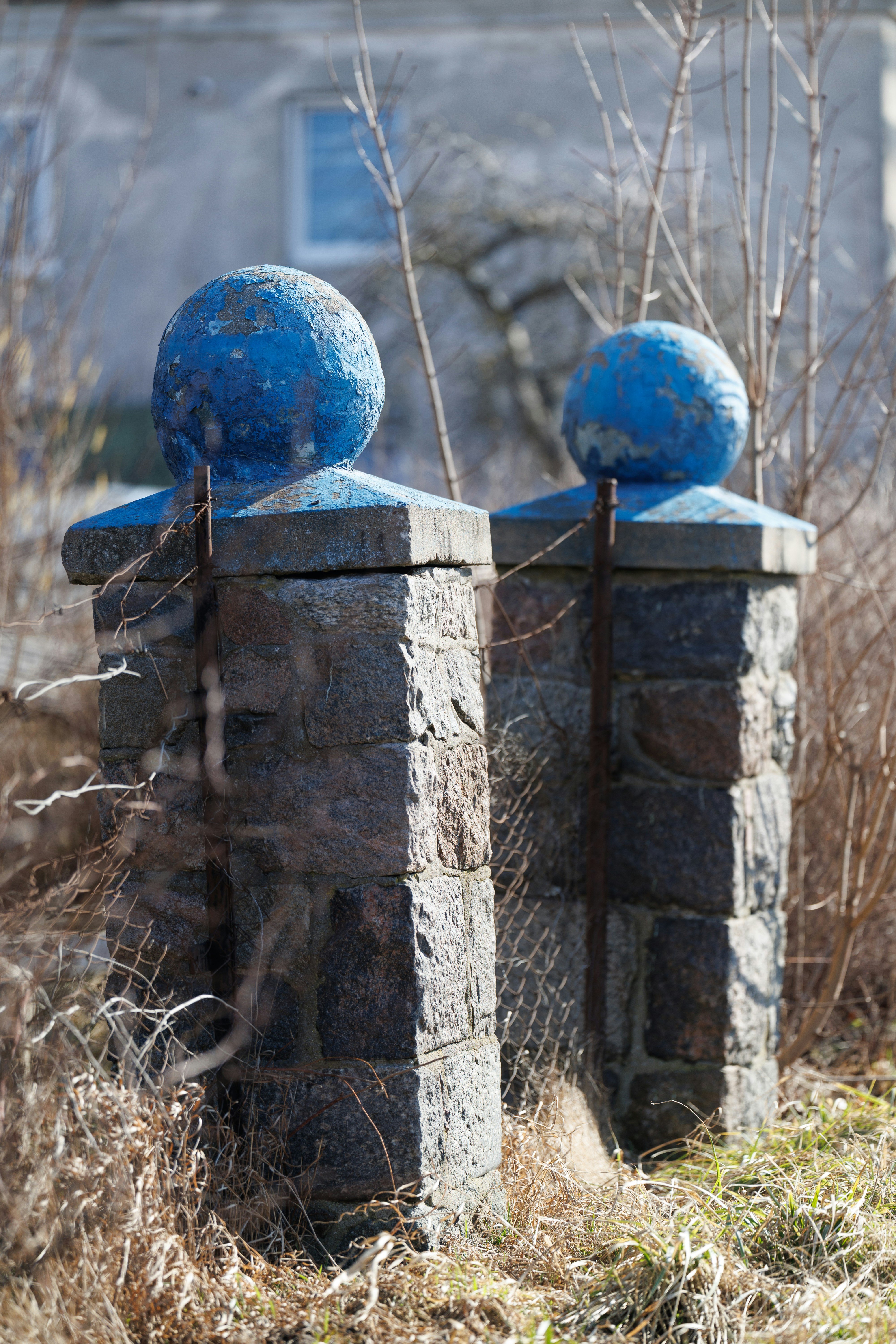 Weathered blue finials Guarding Overgrown Grounds