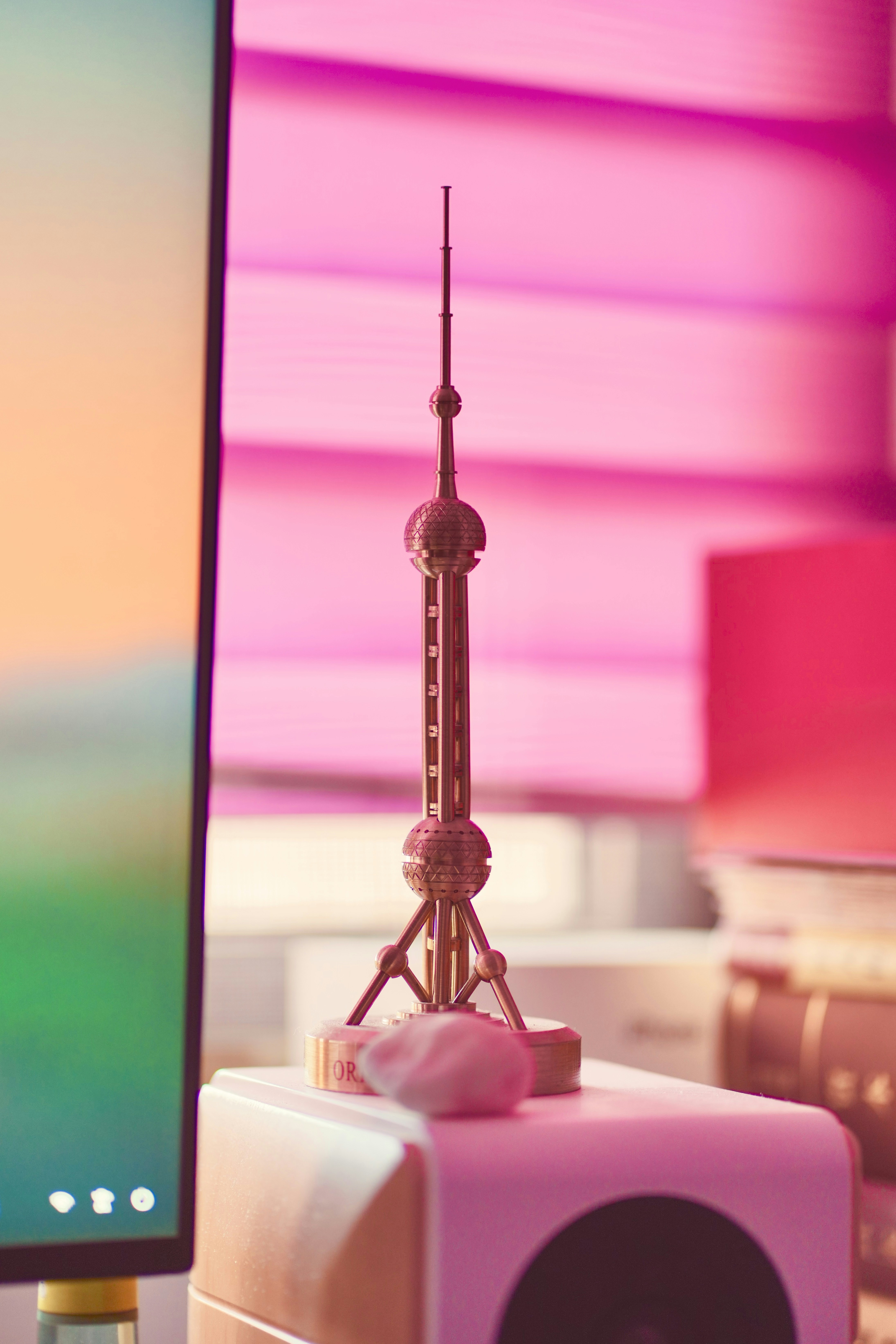 Miniature Skyline on a Desk: A Tower Reaches Toward Neon Pink Light