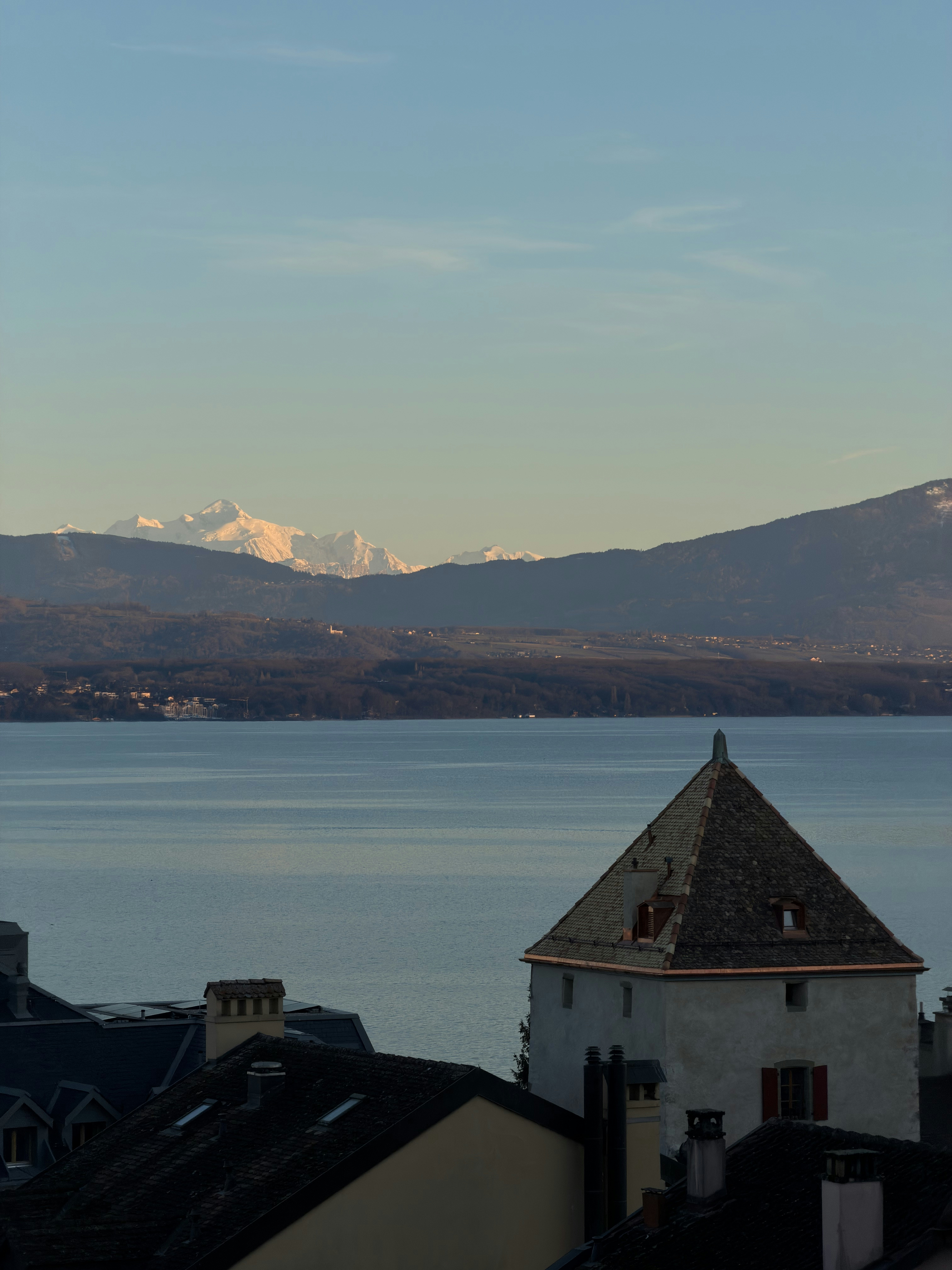 Snow-capped Peaks Over a Quiet Lake Behind Rooftops