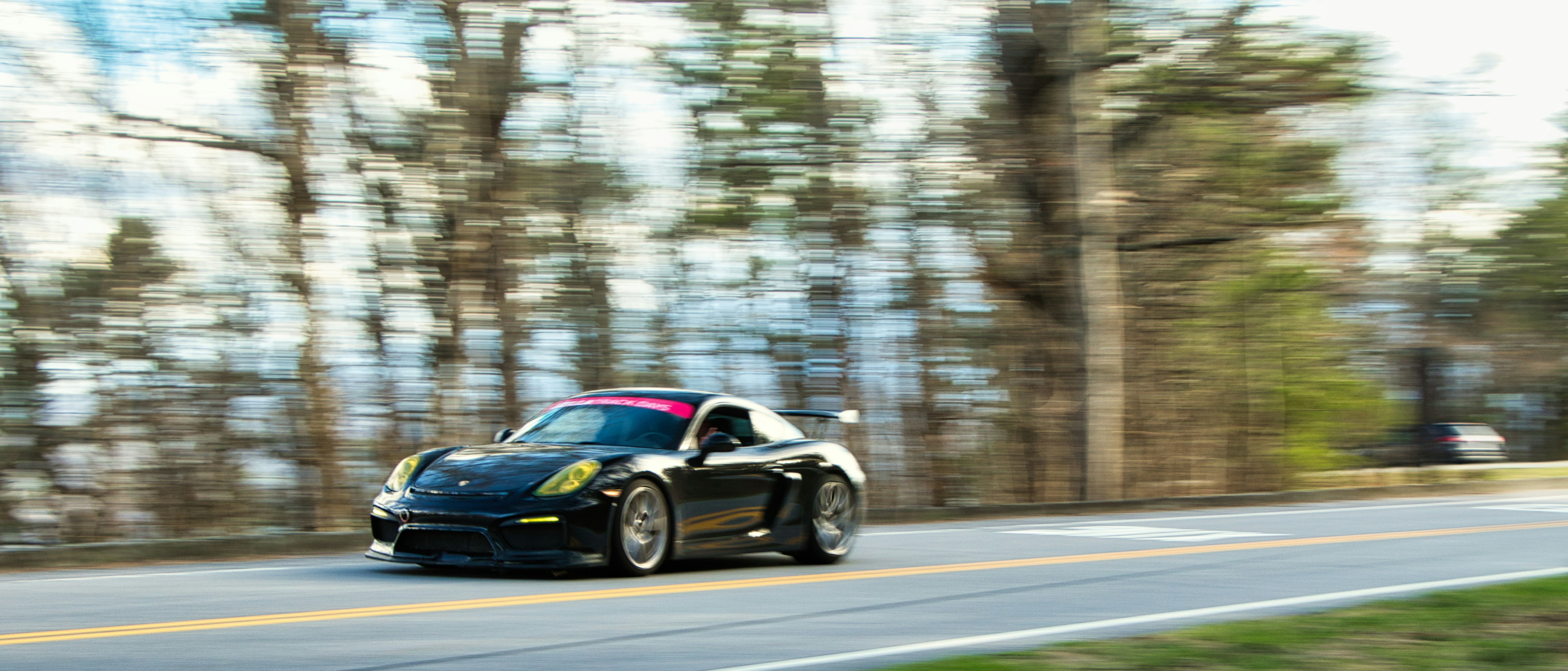 Turbocharged Thunder: A Black Convertible Surges Down a Lined Road