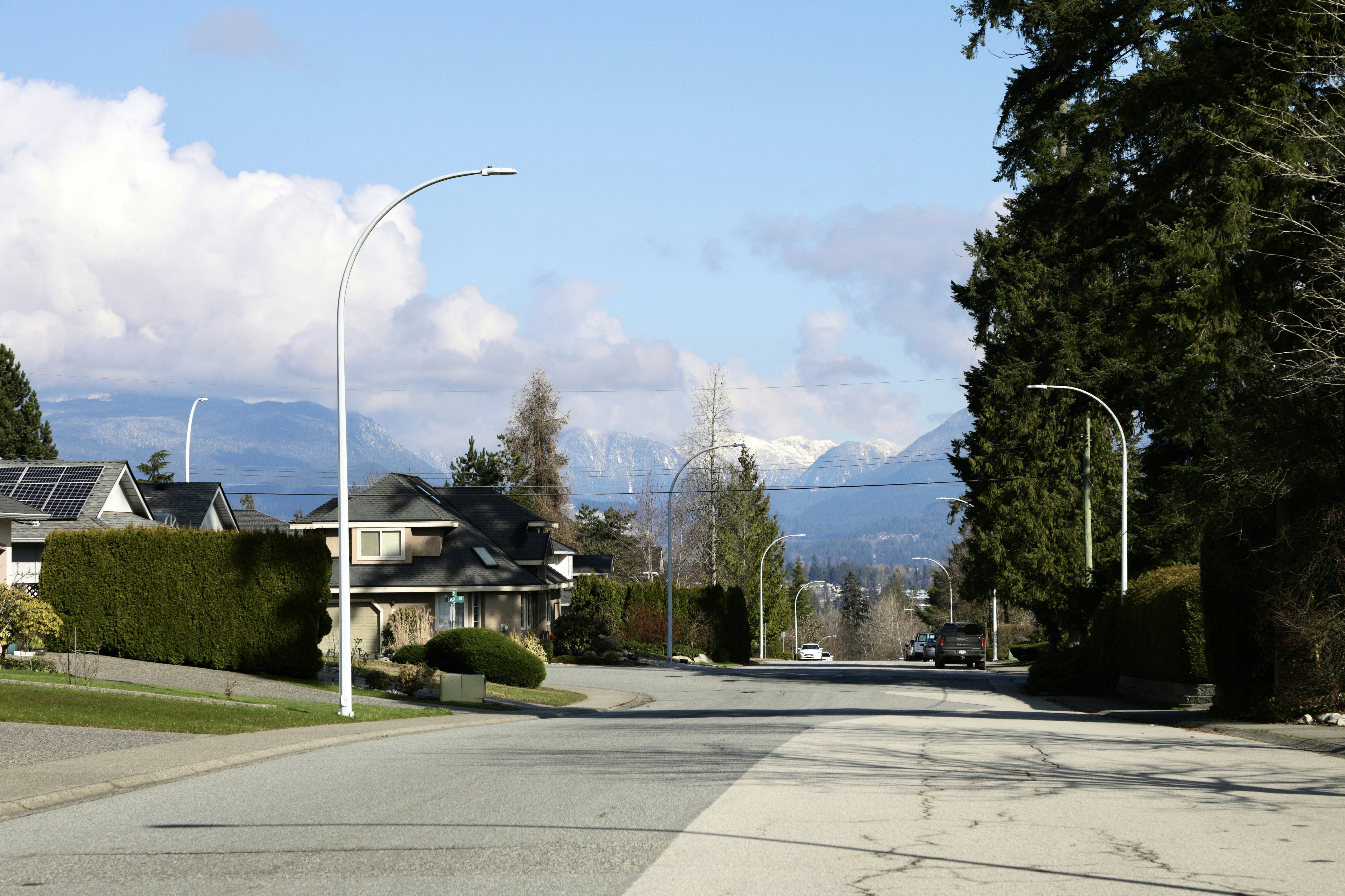 Quiet suburban avenue with distant mountains under a bright sky