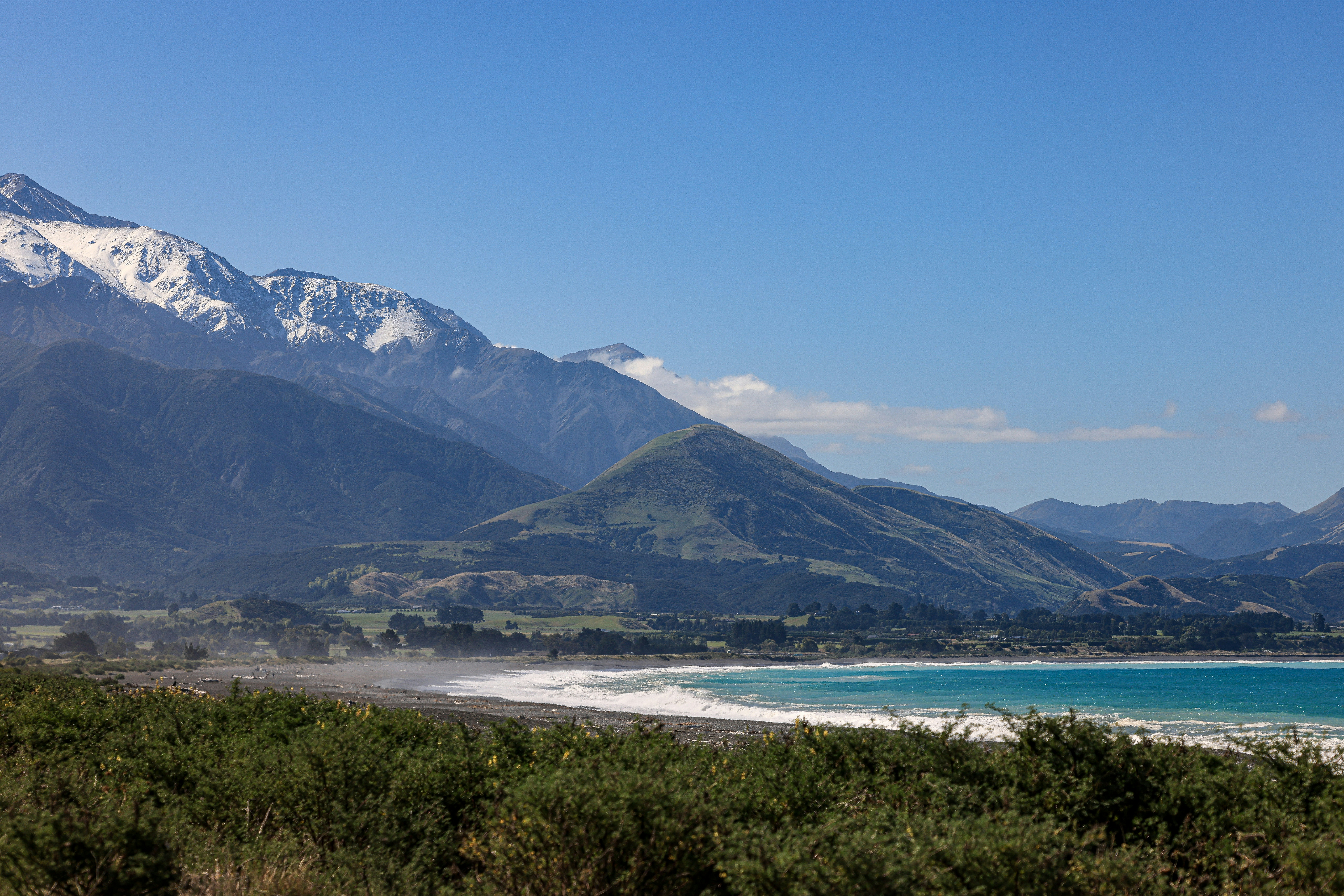 Coastal Ridge beneath Snow-dusted Peaks at Noon