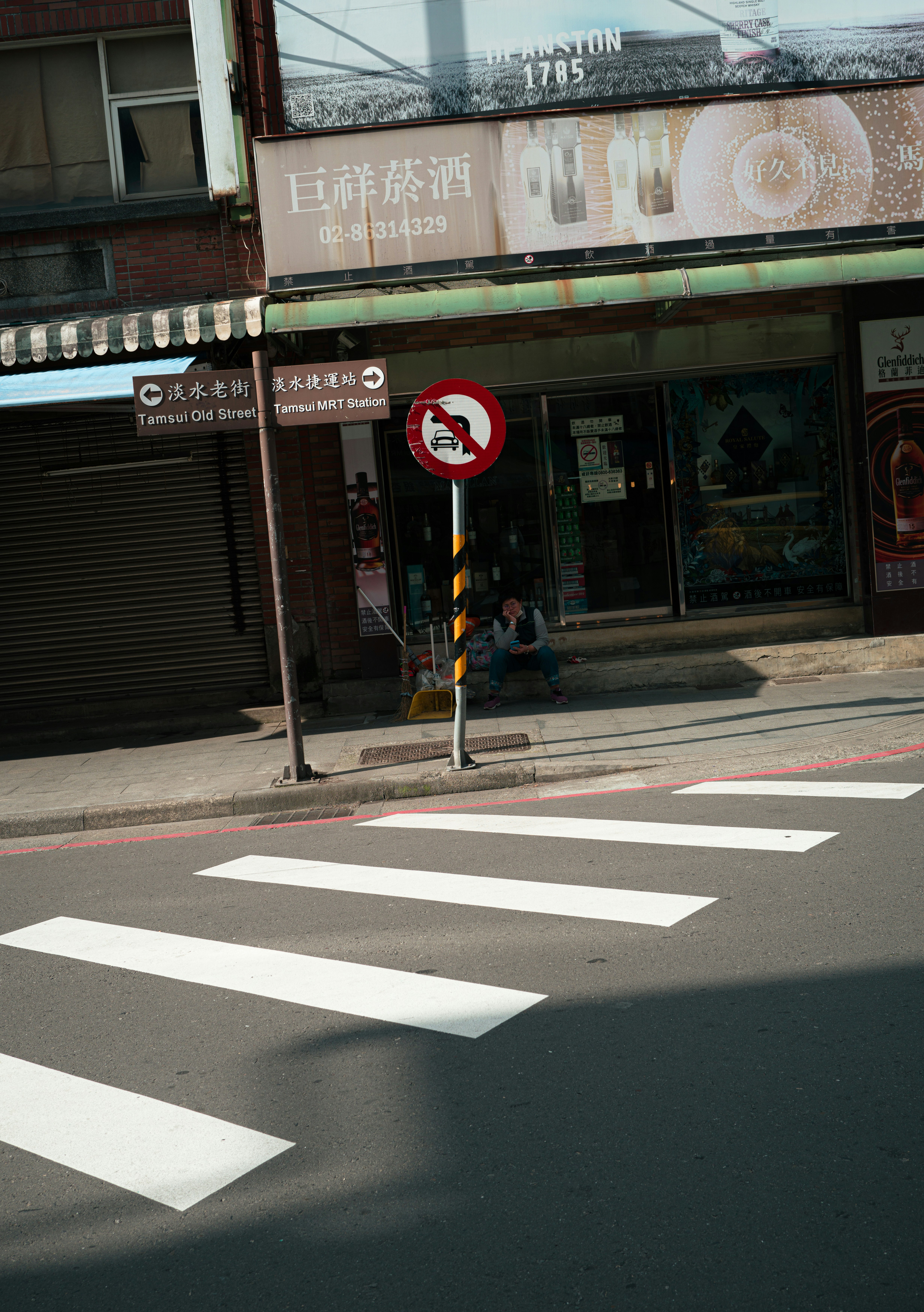 Crosswalk Corner: A Quiet Street Scene Under a Shaded Sign