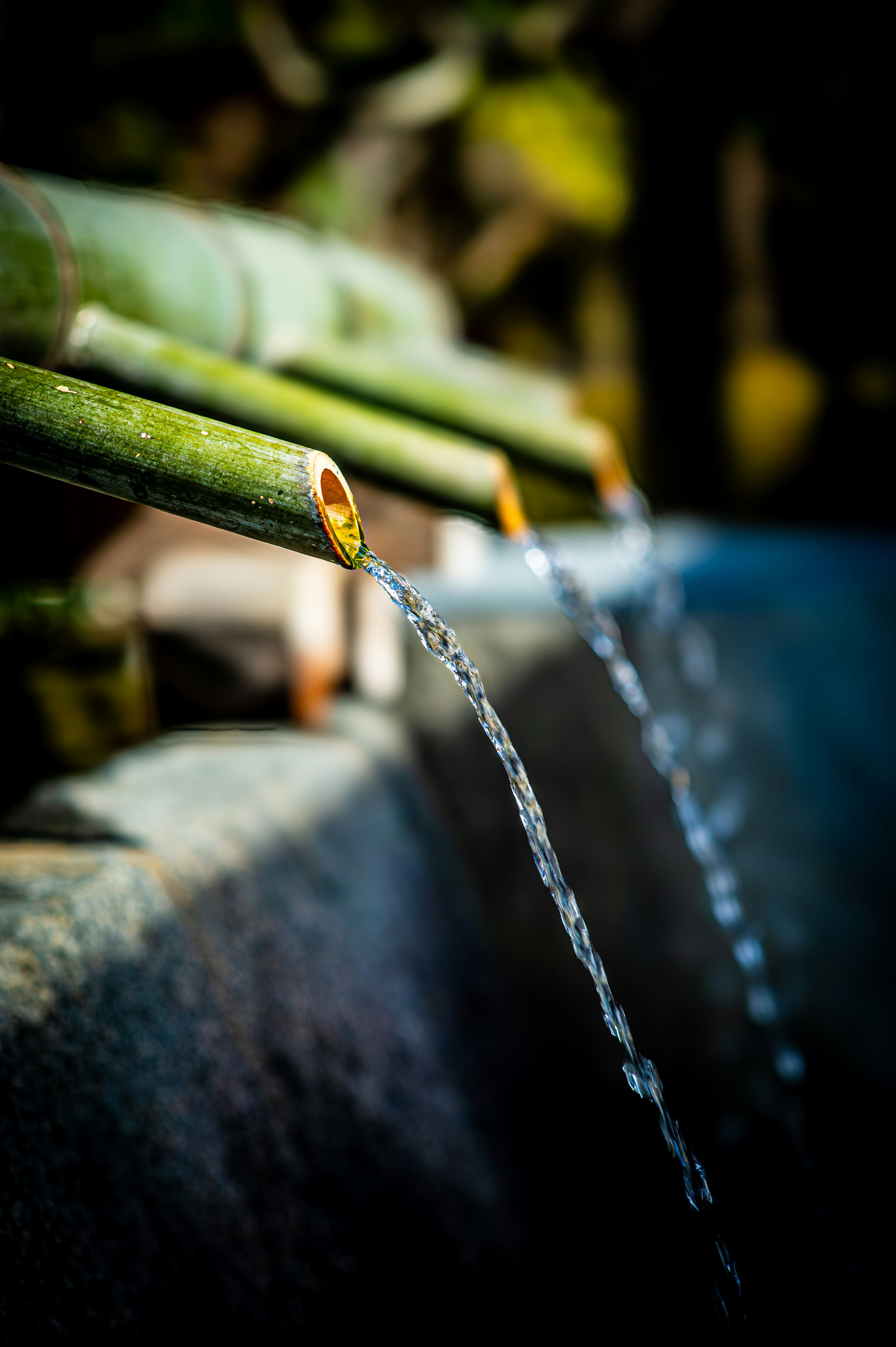 Bamboo spouts pouring a tranquil line of water over a stone channel