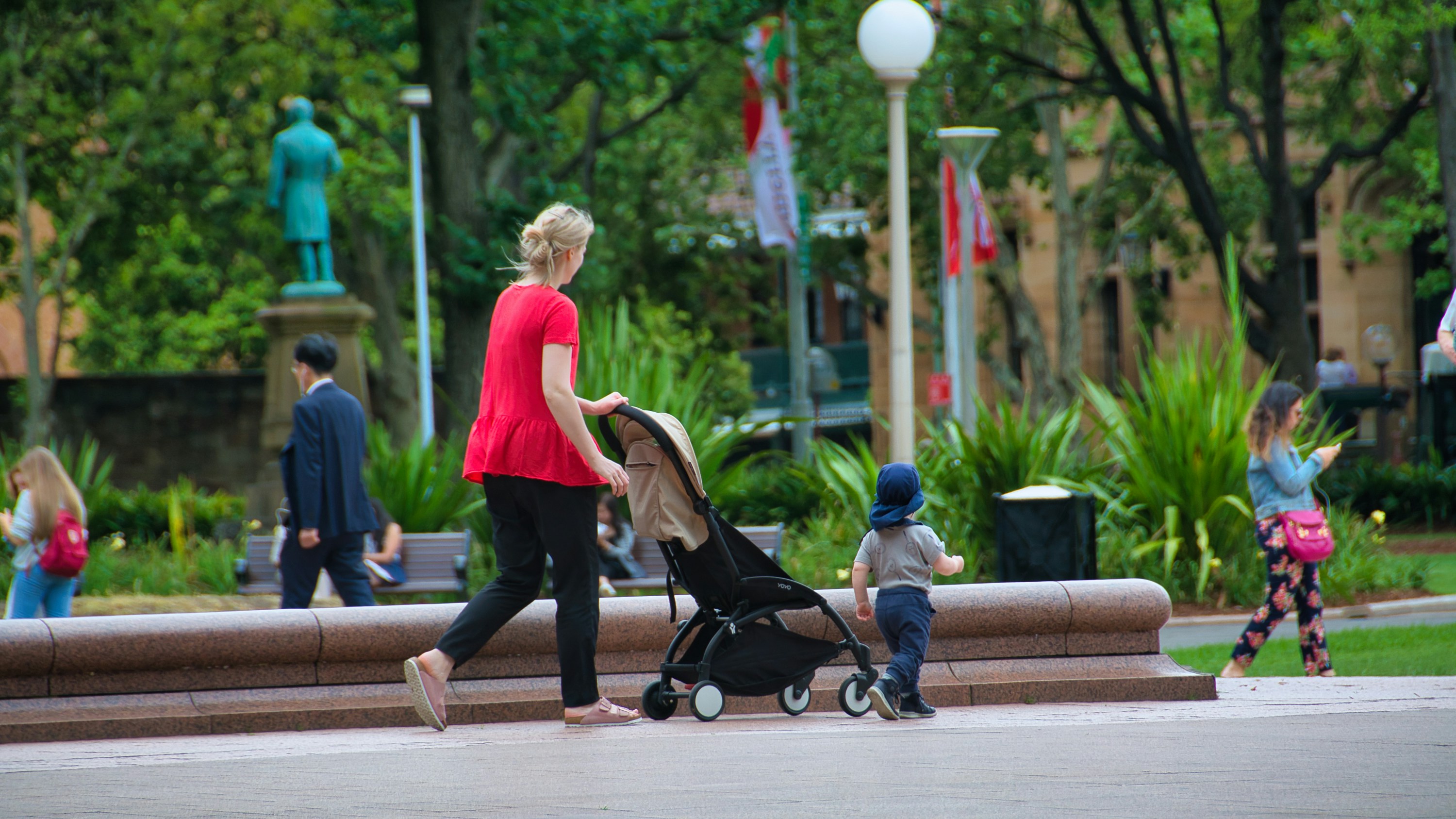 Mother and stroller in motion along a park walkway