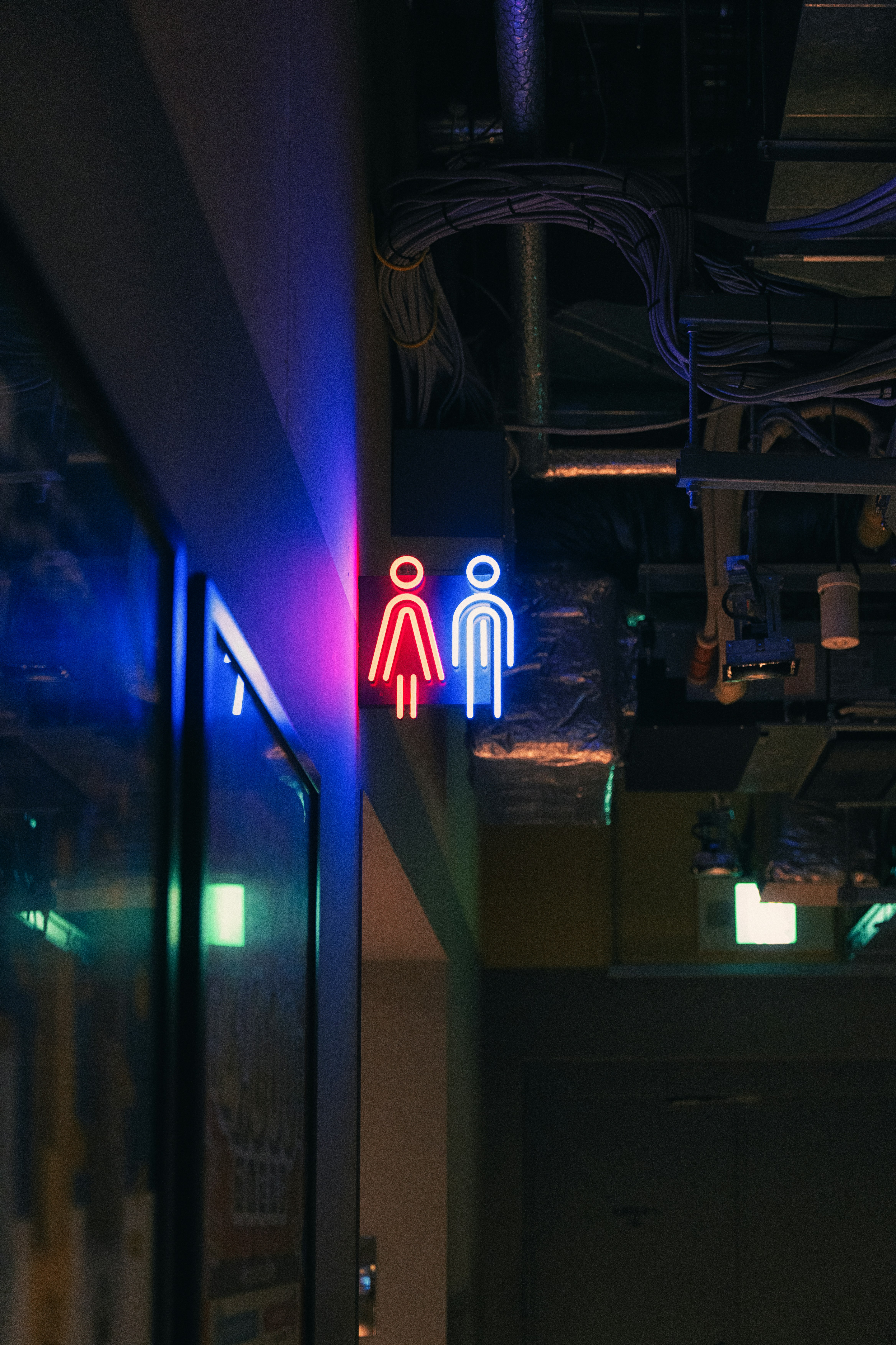 Neon Duo: Red and Blue Figures Hover in a Dim Corridor