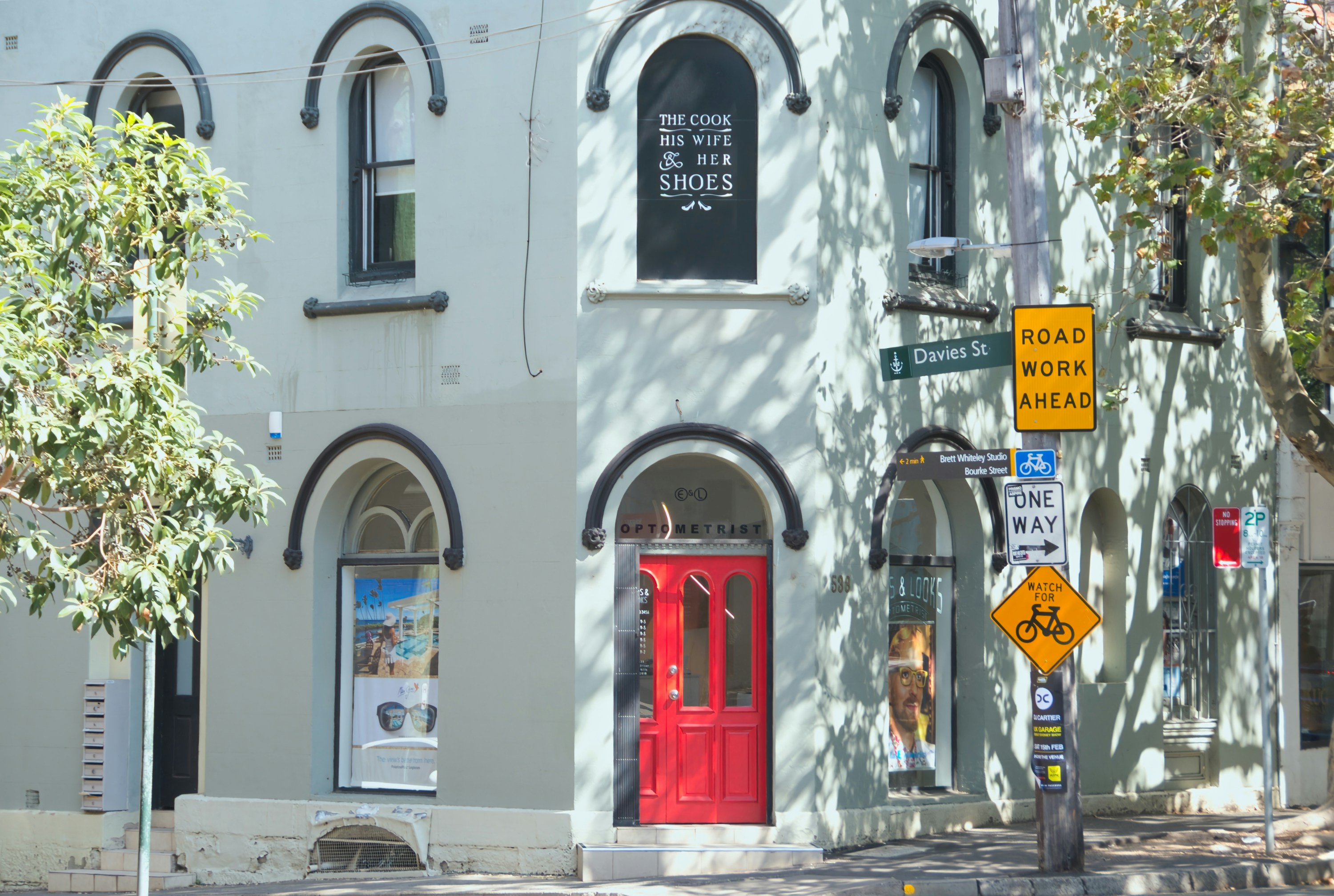 Red Door at a Sunlit Corner: Historic Building with Street Signage