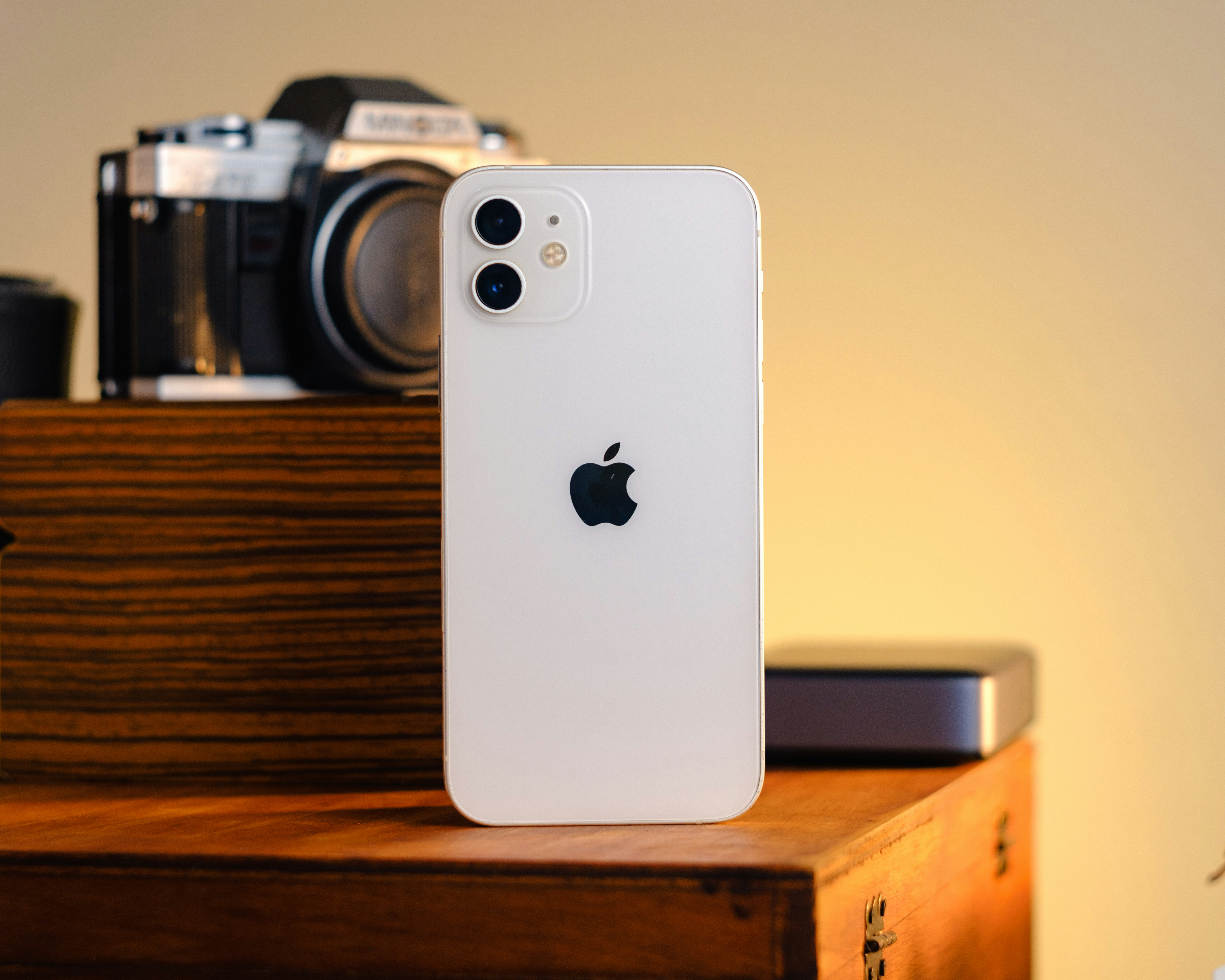 White iPhone Portrait on Wooden Table with Vintage Camera in Soft Light