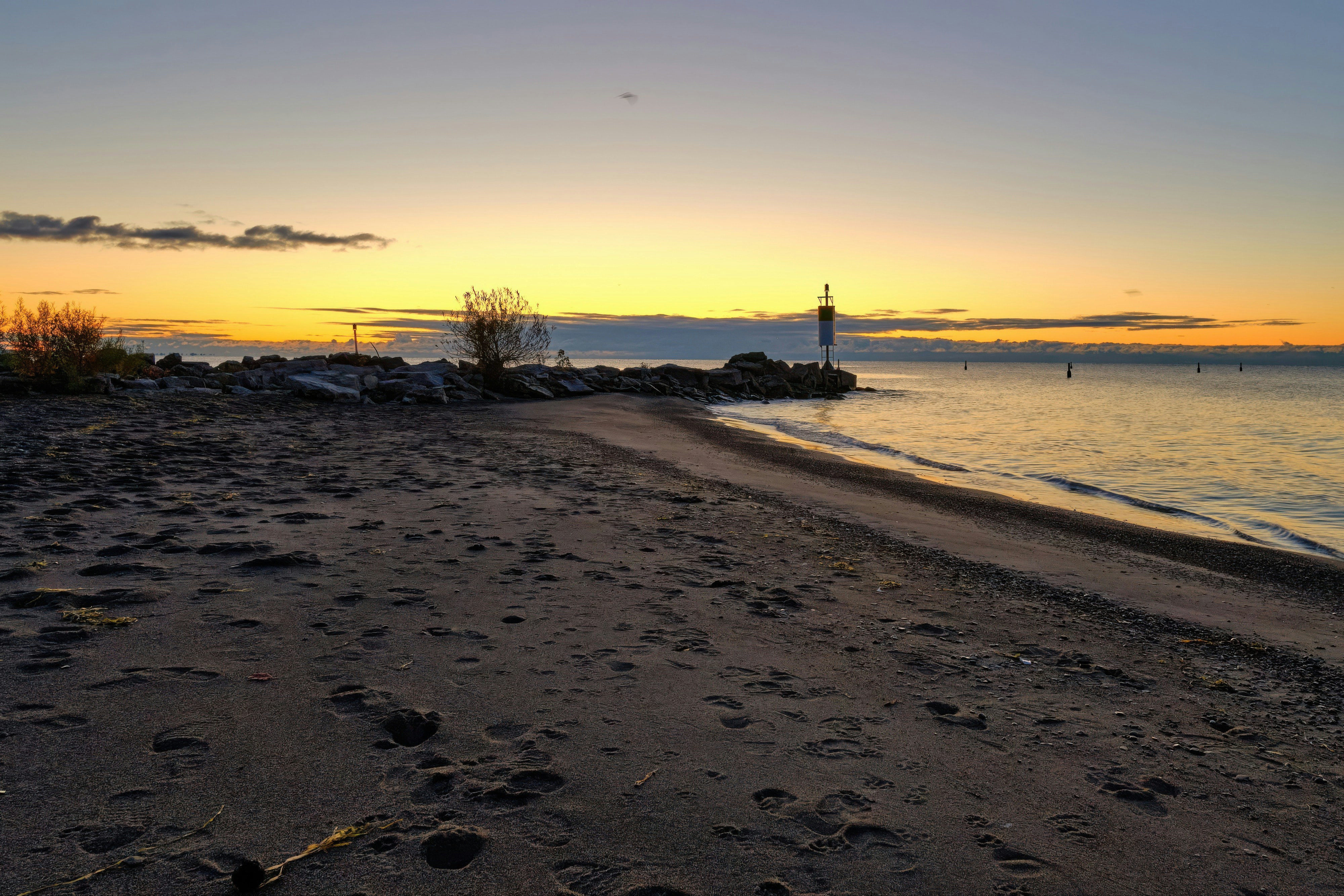 Dusk at the Breakwater: A Quiet Beach with a Lone Beacon