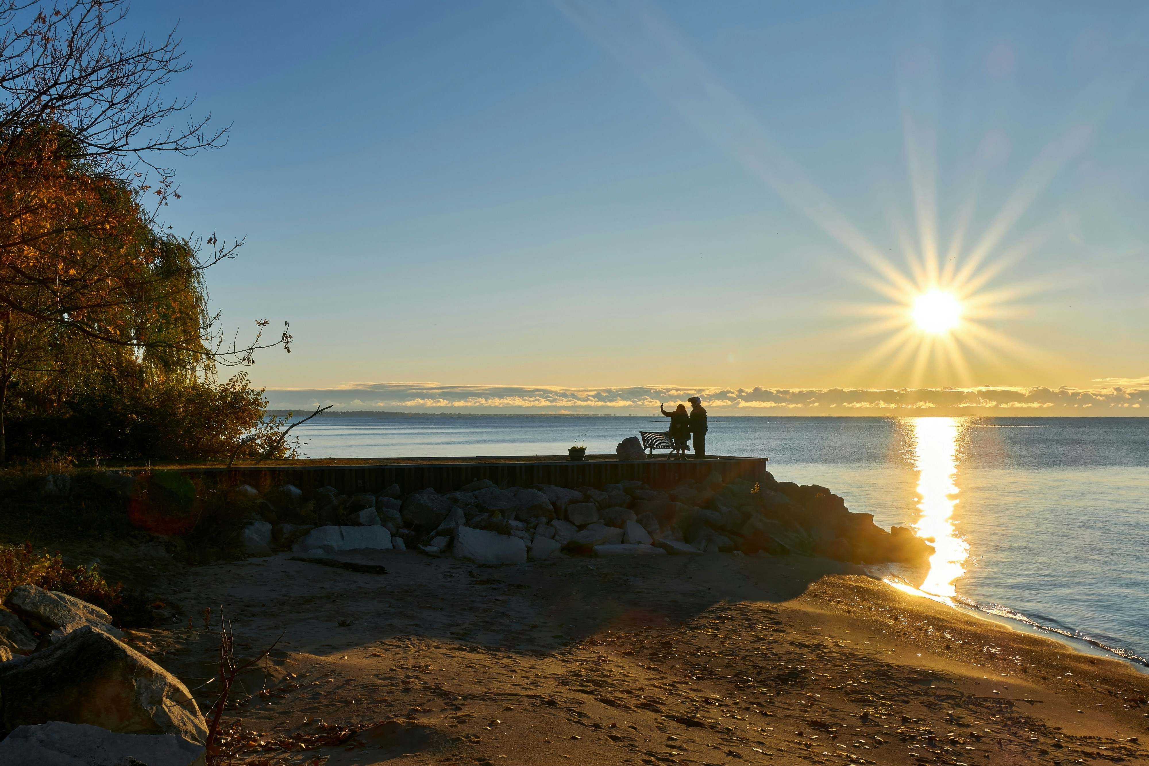 Sunlit couple at the edge of the jetty as waves kiss the shore