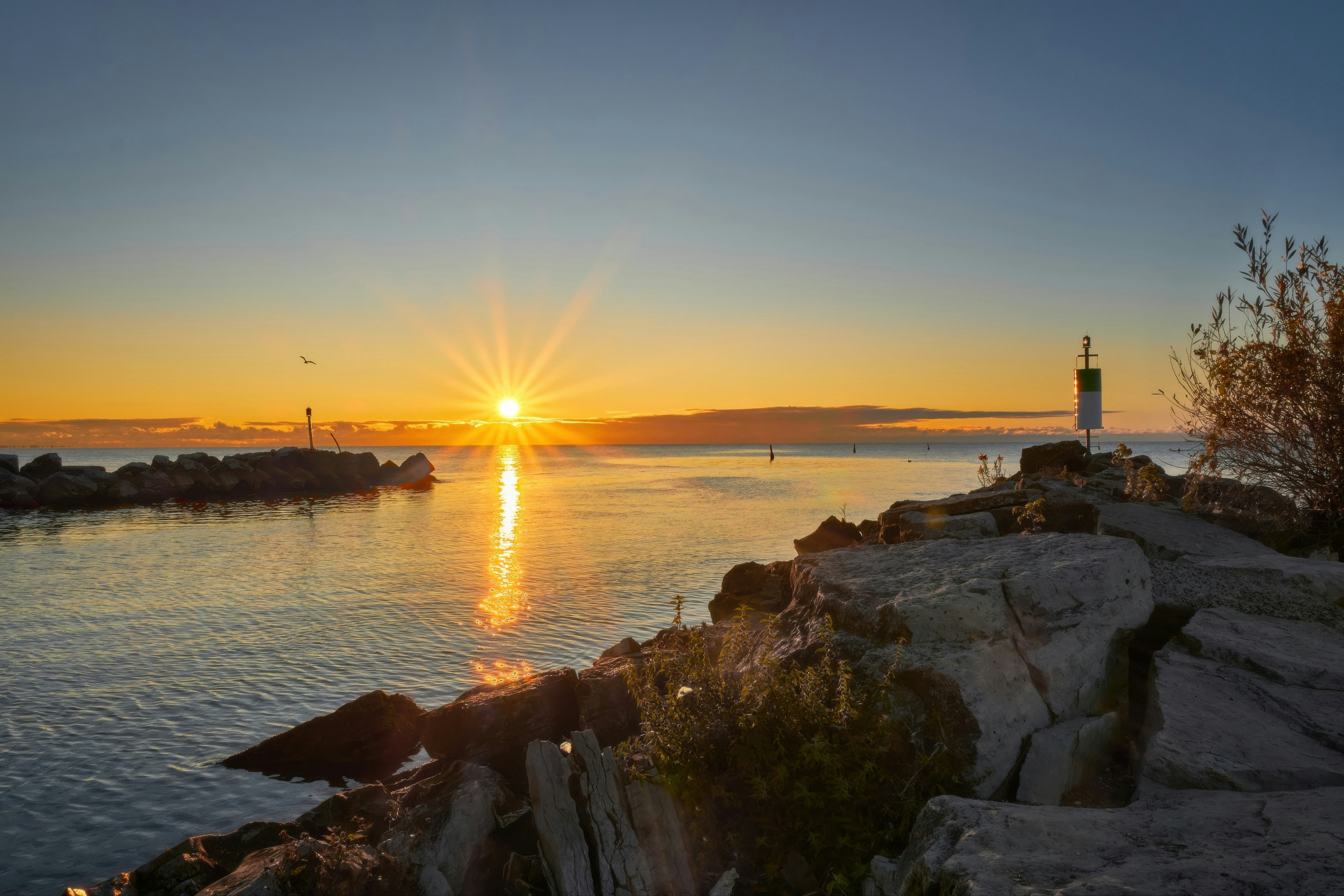 Sunrise Over a Rocky Breakwater with a Lighthouse at the Horizon