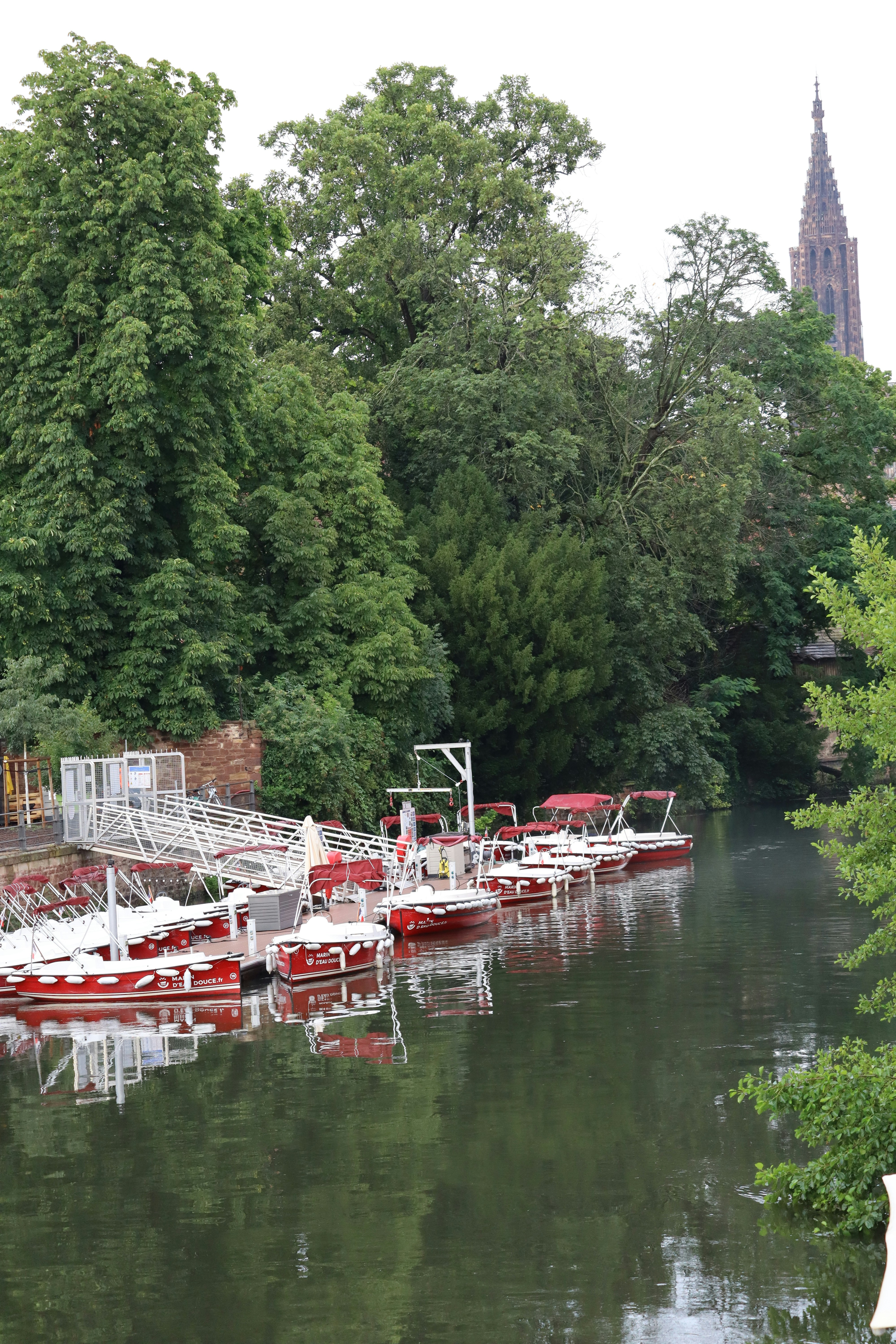 Red-boat Marina along a Green River with a Gothic Tower Peeking Through