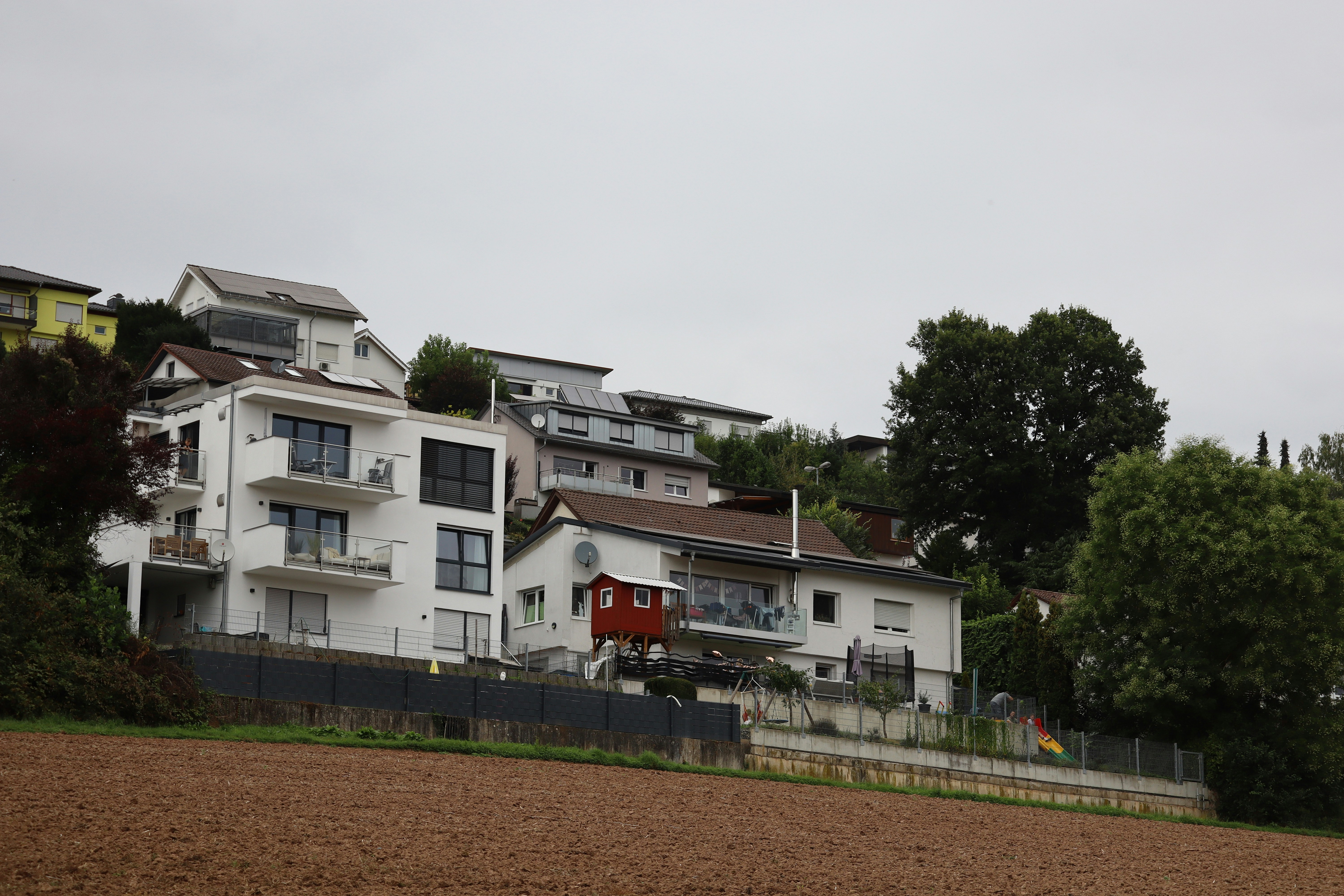 Row of modern houses perched above a tilled field