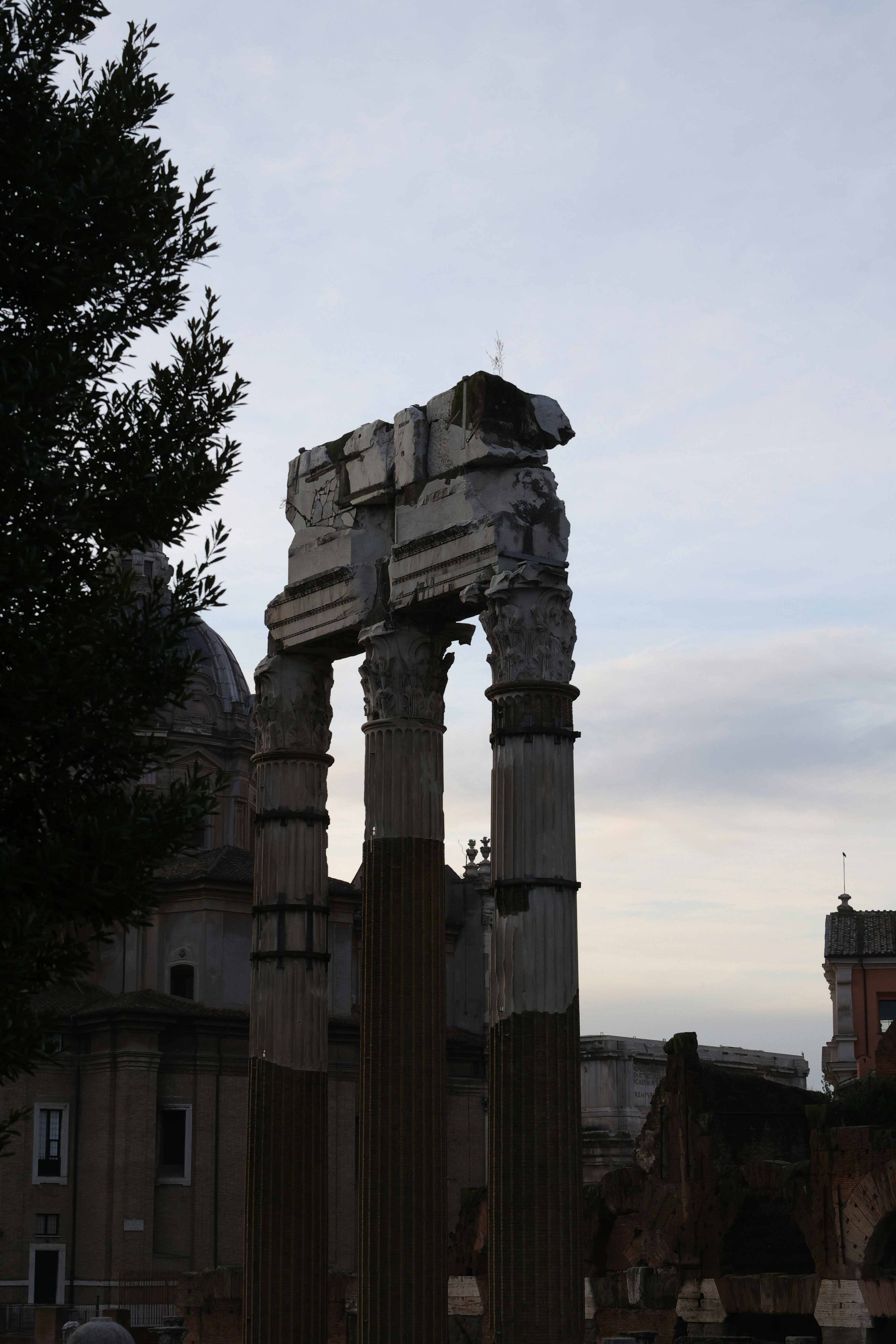 Ruins of the Three-Column Gateway Against a City Sky