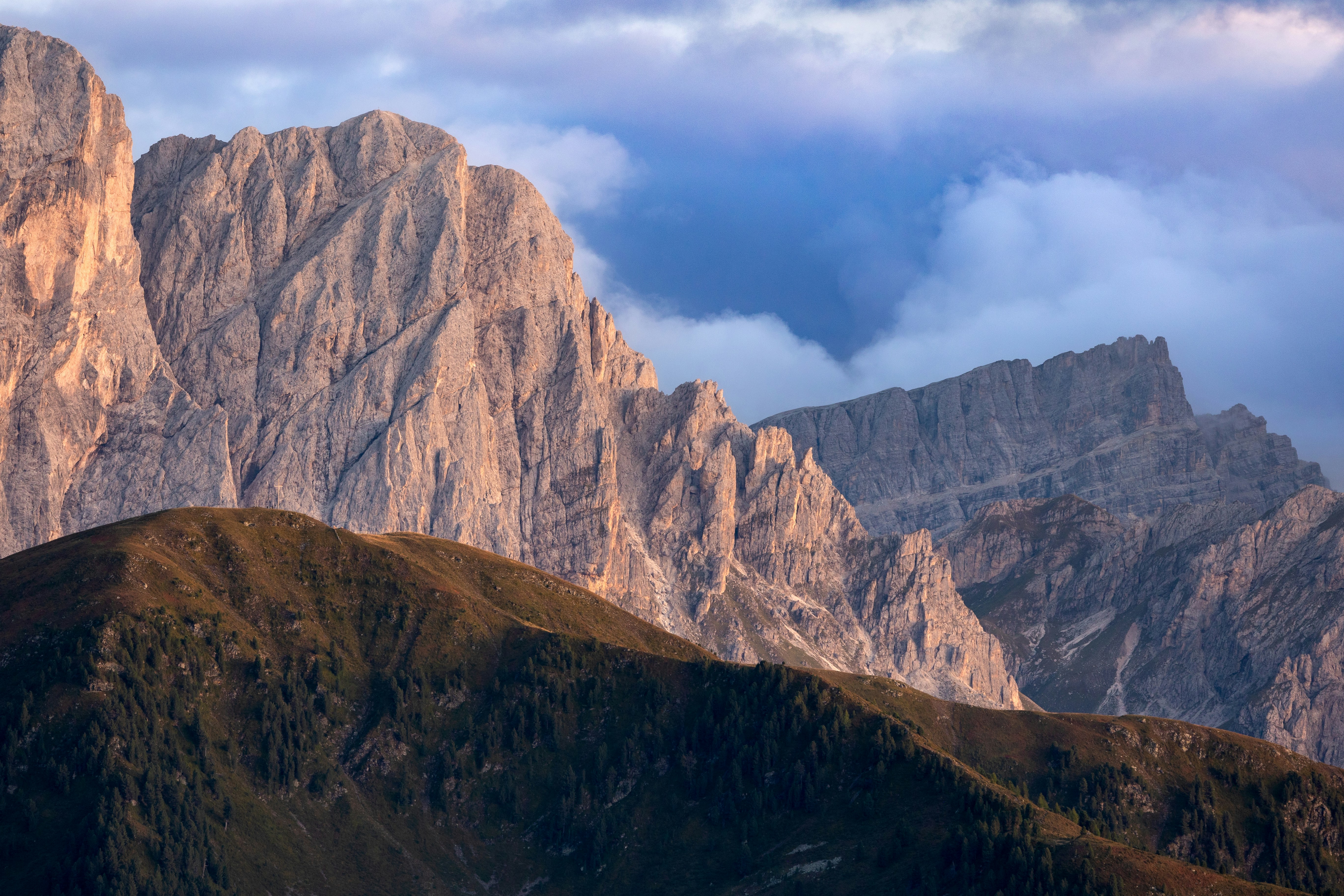Jagged mountain peaks bathed in warm sunlight under clouds
