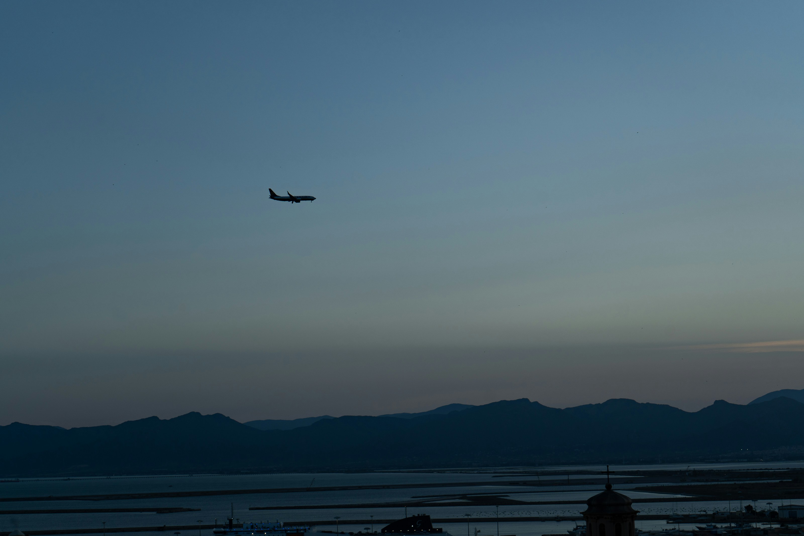 Silent Horizon: A lone jet over distant ridges at blue hour