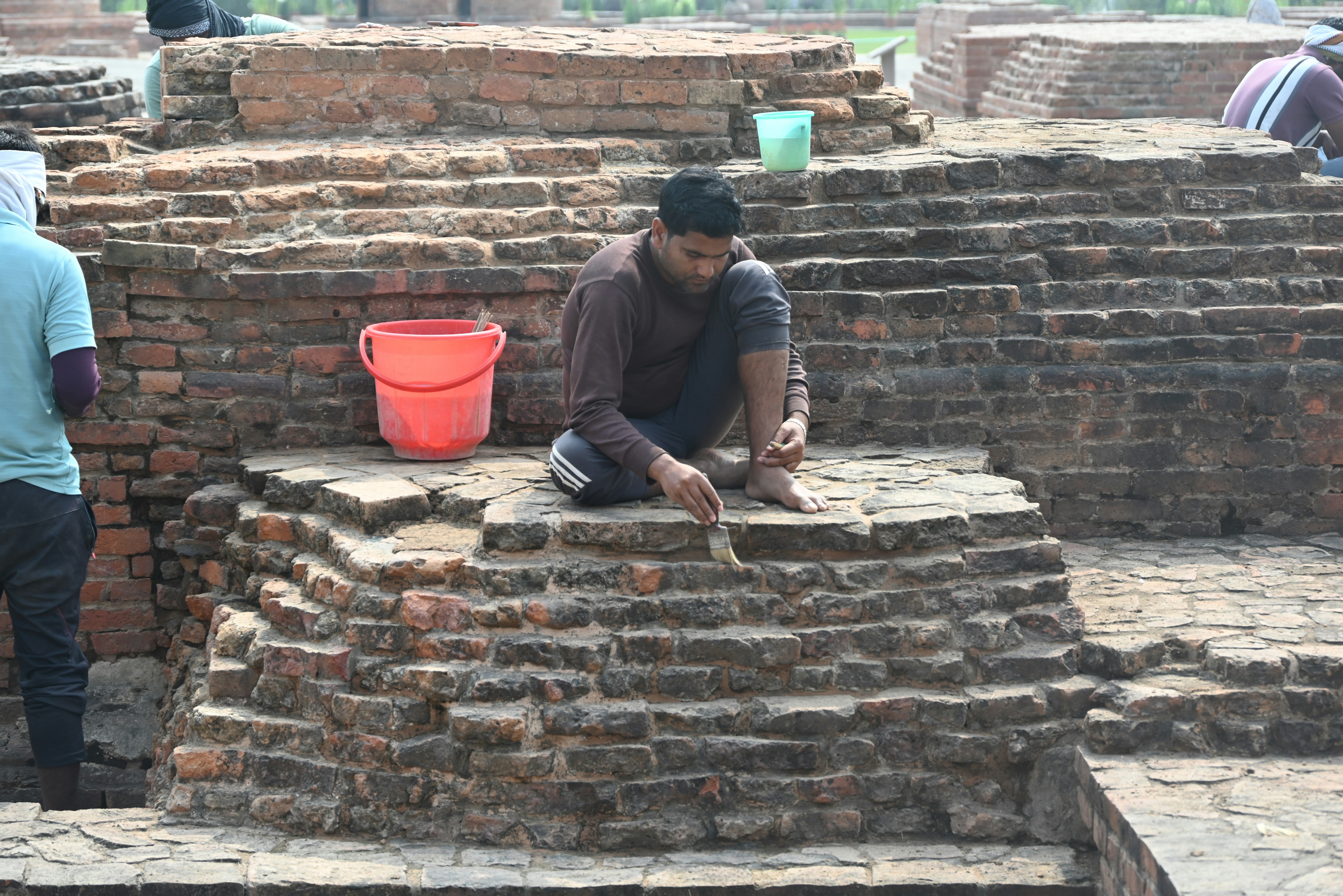 Man working at ancient brick ruins with bucket