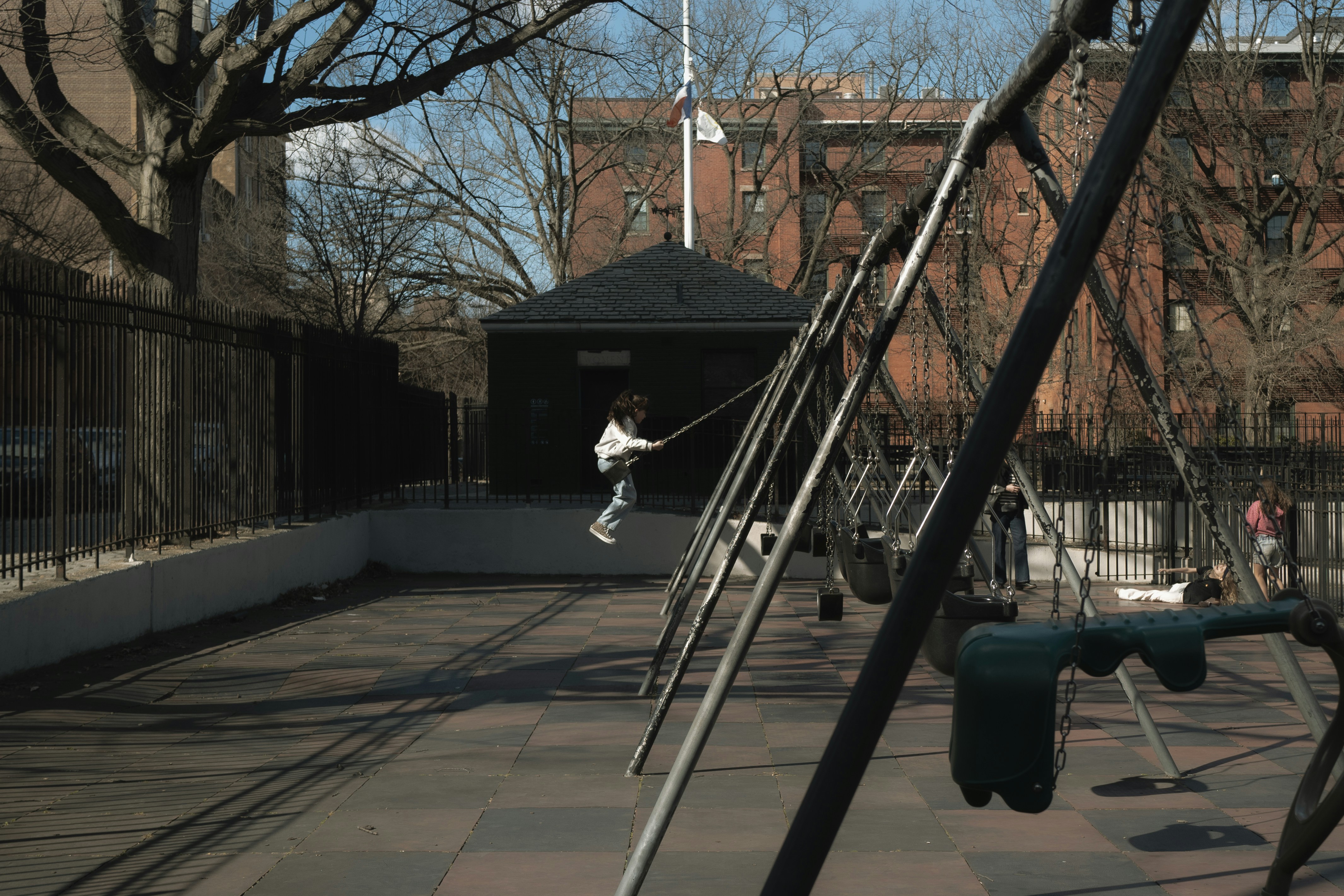 Swinging Against the City: A Lone Moment in the Playground