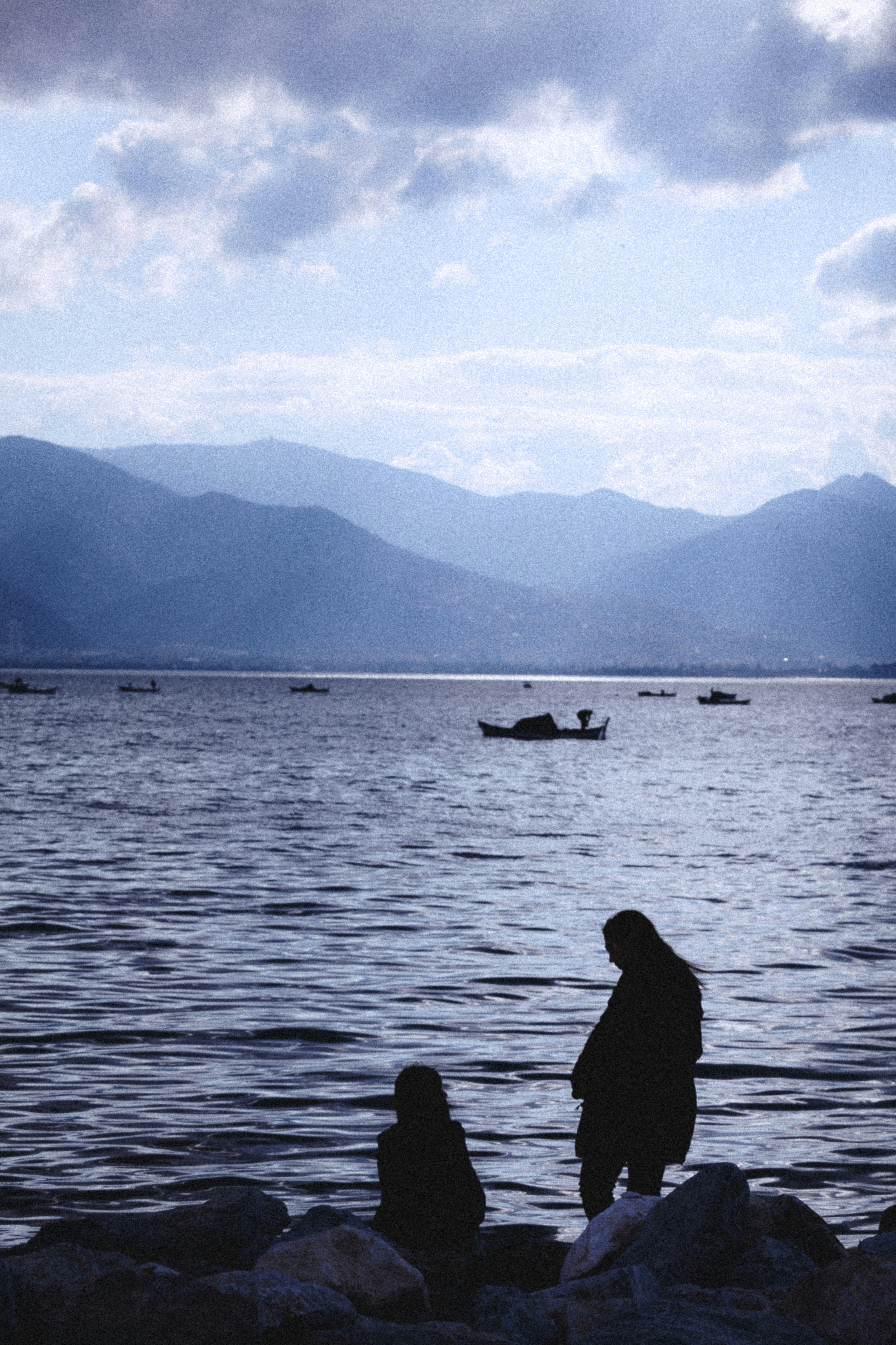 Silhouettes at Dusk: A Quiet Moment by the Lake