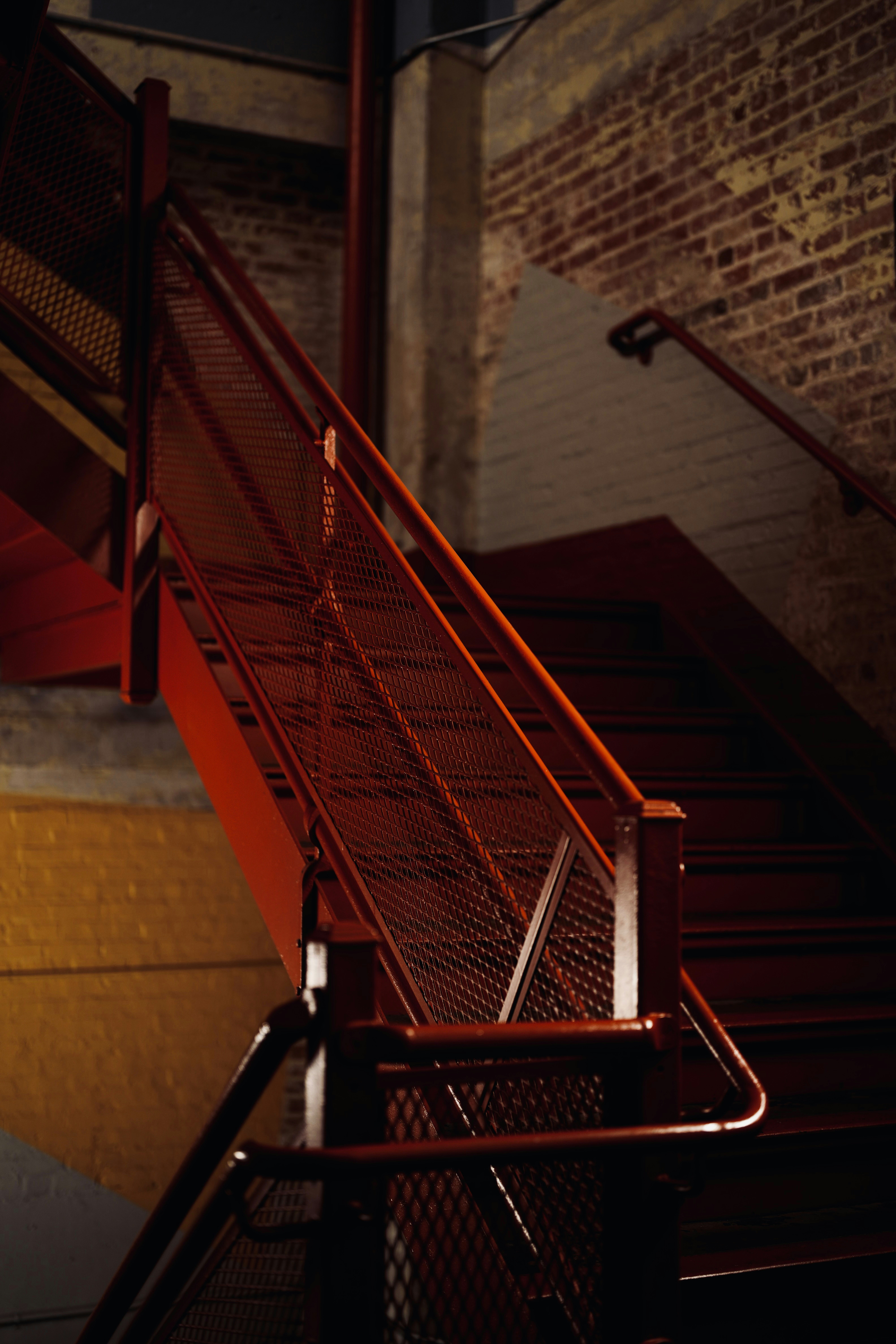 Industrial Descent: Red Staircase Echoes in a Dim Factory