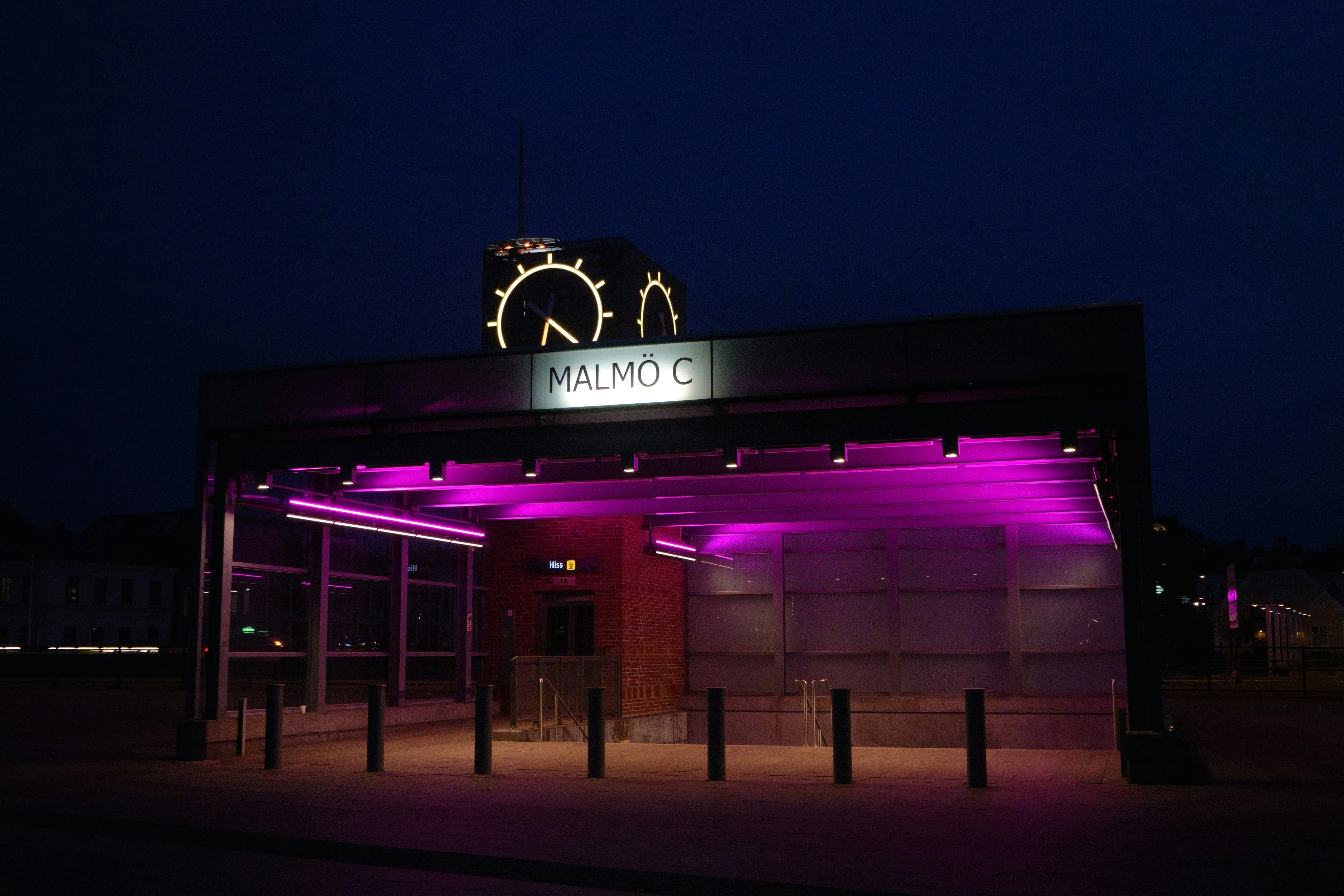 Neon-lit Malmo C Station Portal Beneath a Midnight Clock