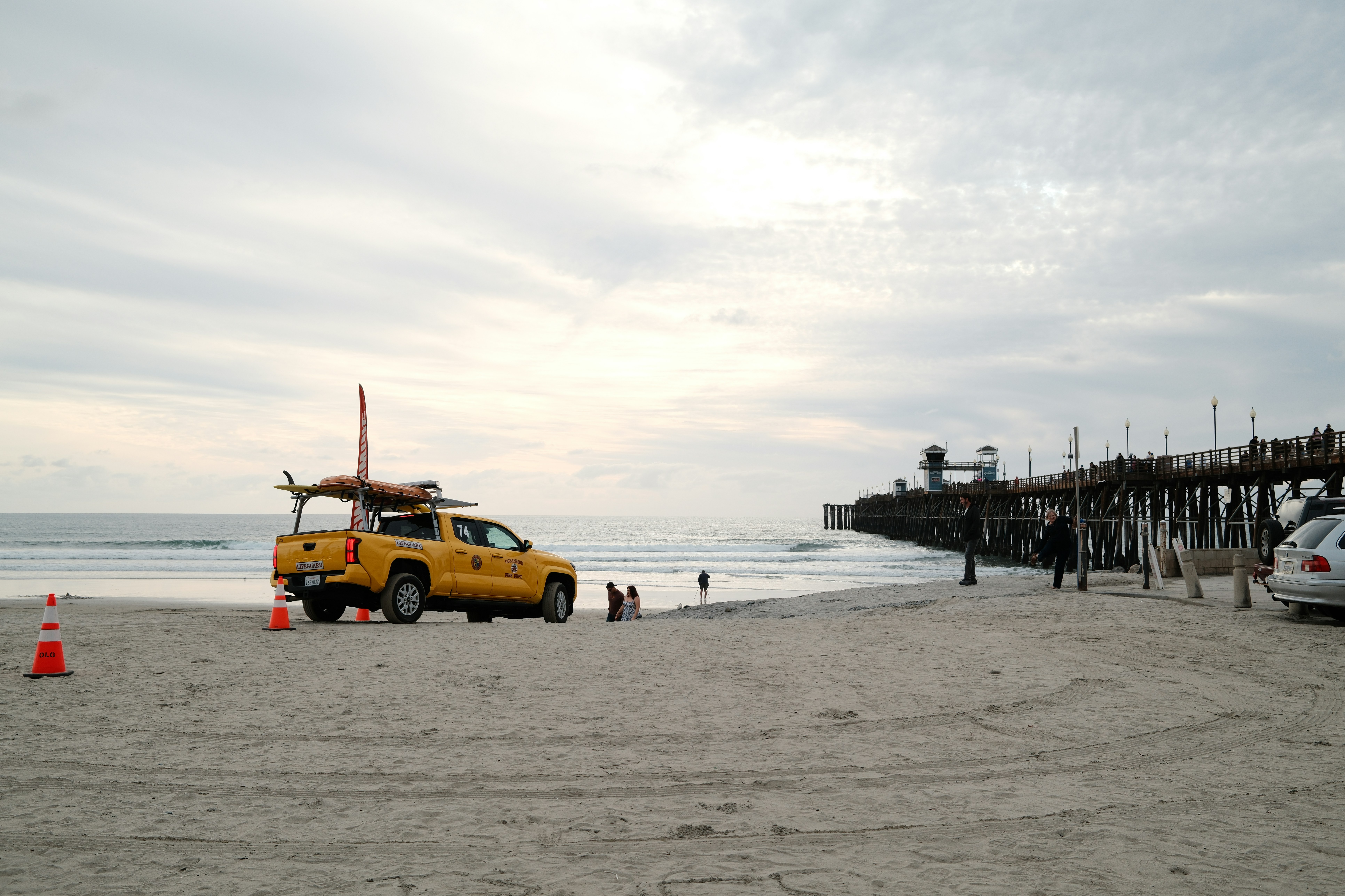 Yellow SUV and Wooden Pier: A Quiet Beach Day by the Surf