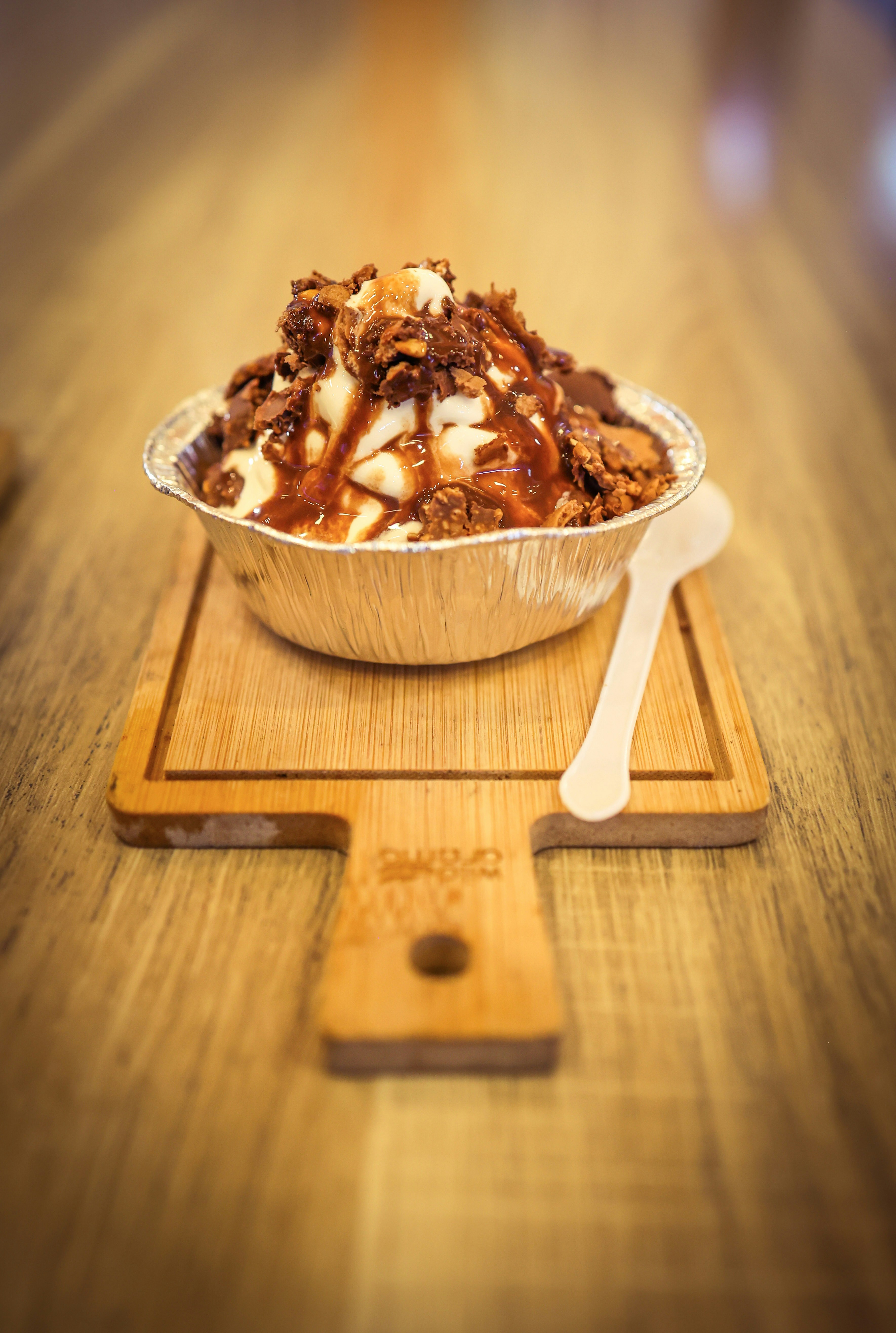 Chocolate-drenched dessert in a metal bowl atop a wooden board