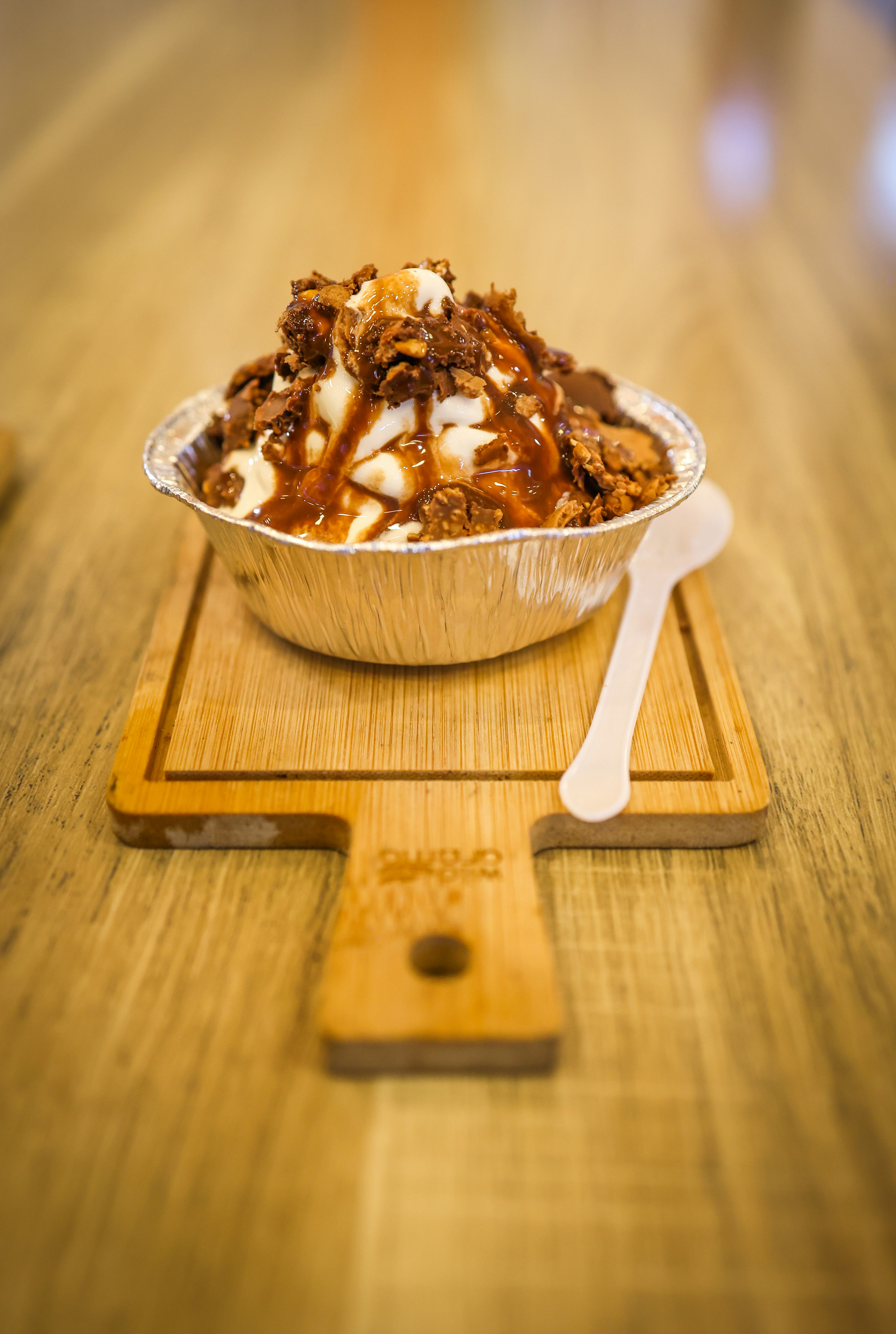 Caramel Sundae in a Shallow Aluminum Bowl on a Wooden Board
