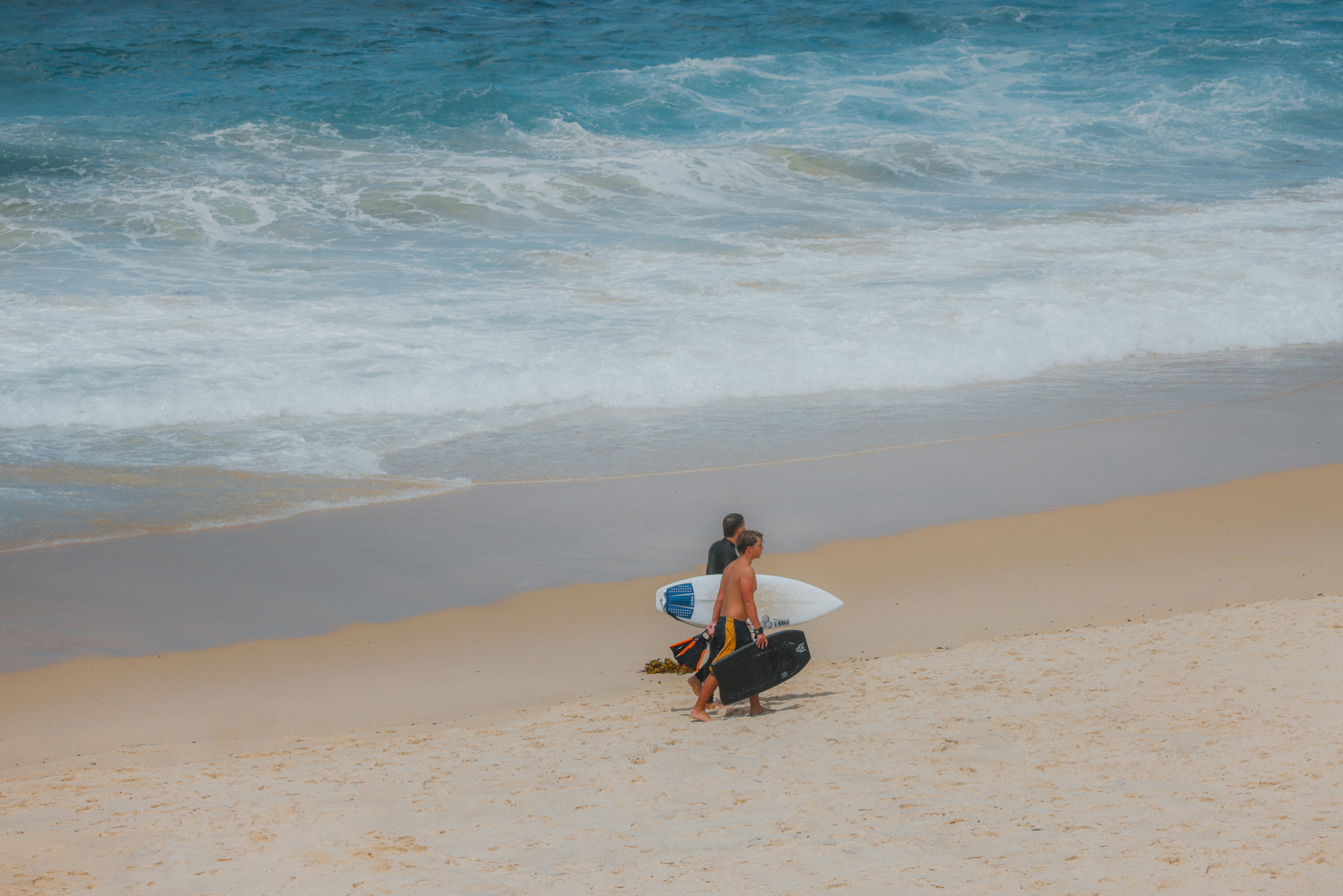 Surfing duo and their boards on sunlit shoreline