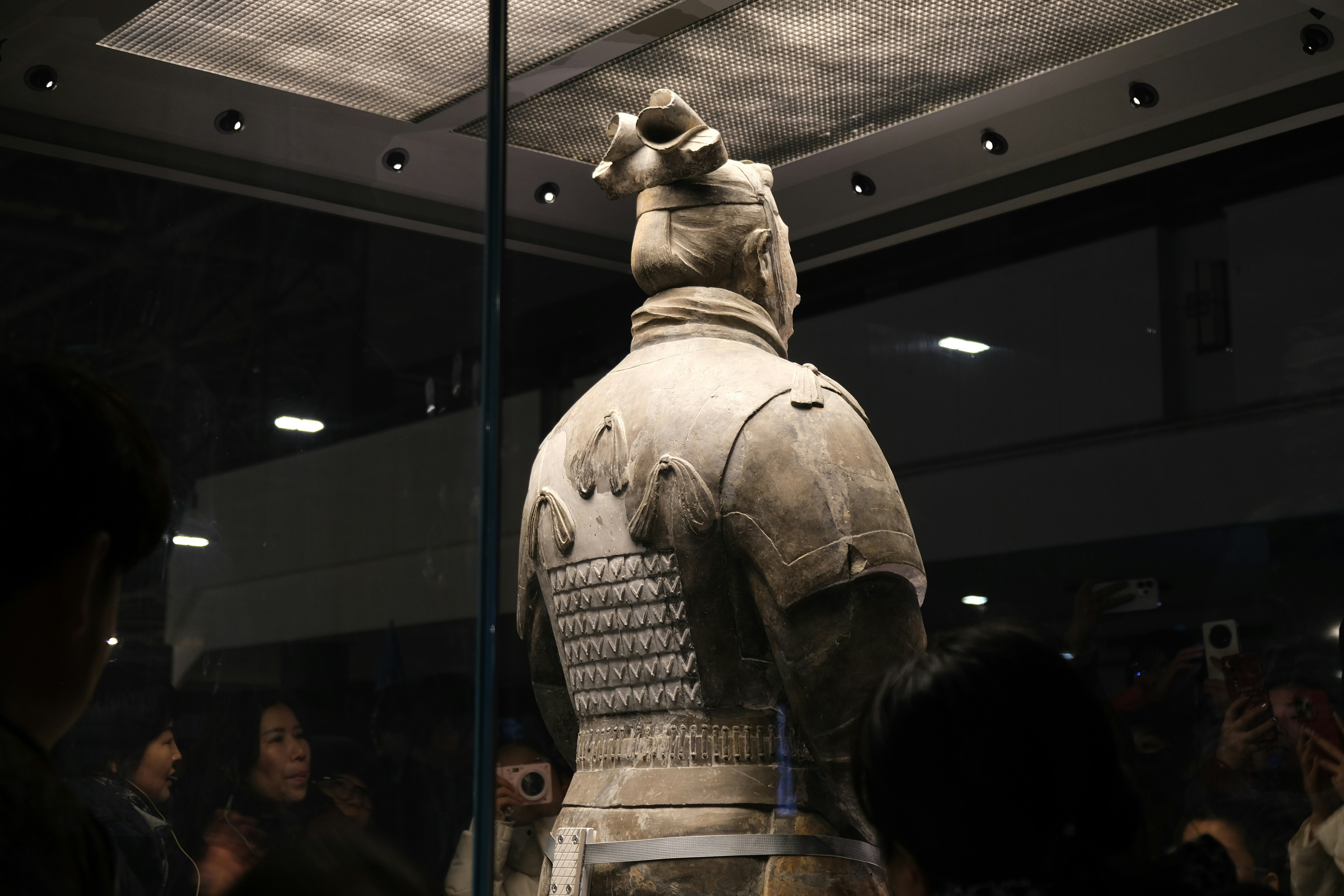 Echoes of Iron: A Terracotta Guardian Framed by Dark Glass