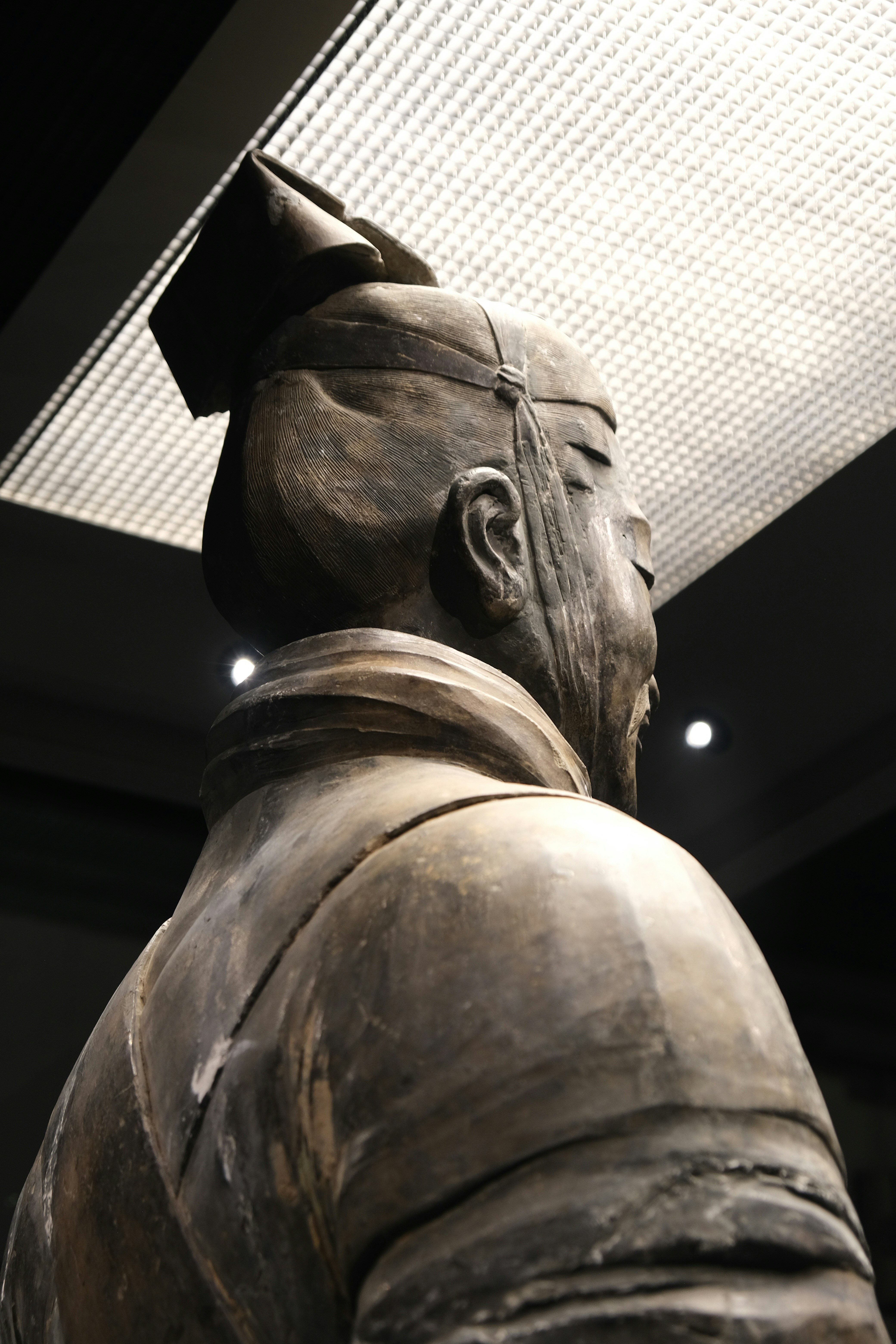 Quiet Resolve: A Bronze Figure Under Fluorescent Light