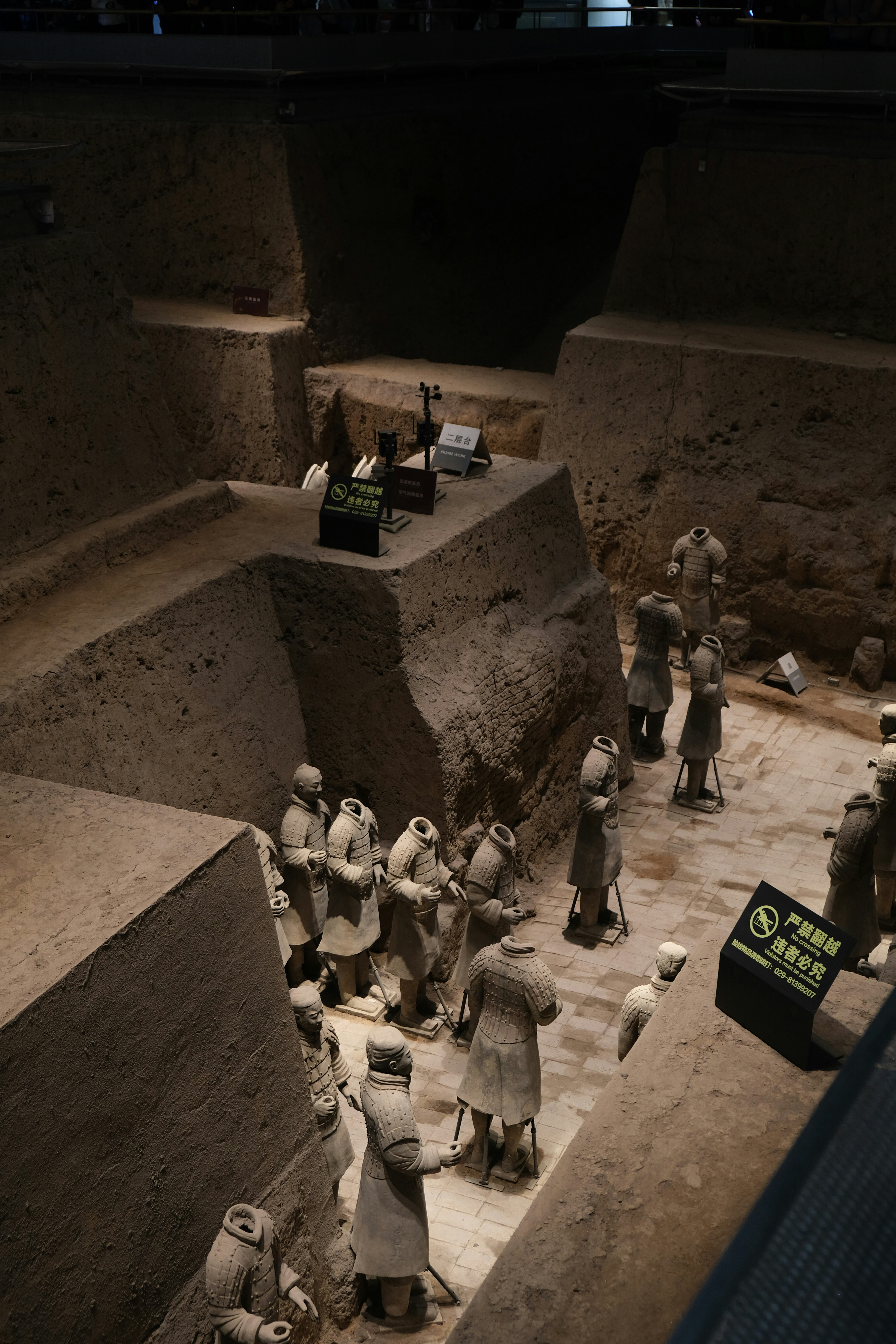 Line of terracotta echoes: soldiers in a sunlit excavation pit