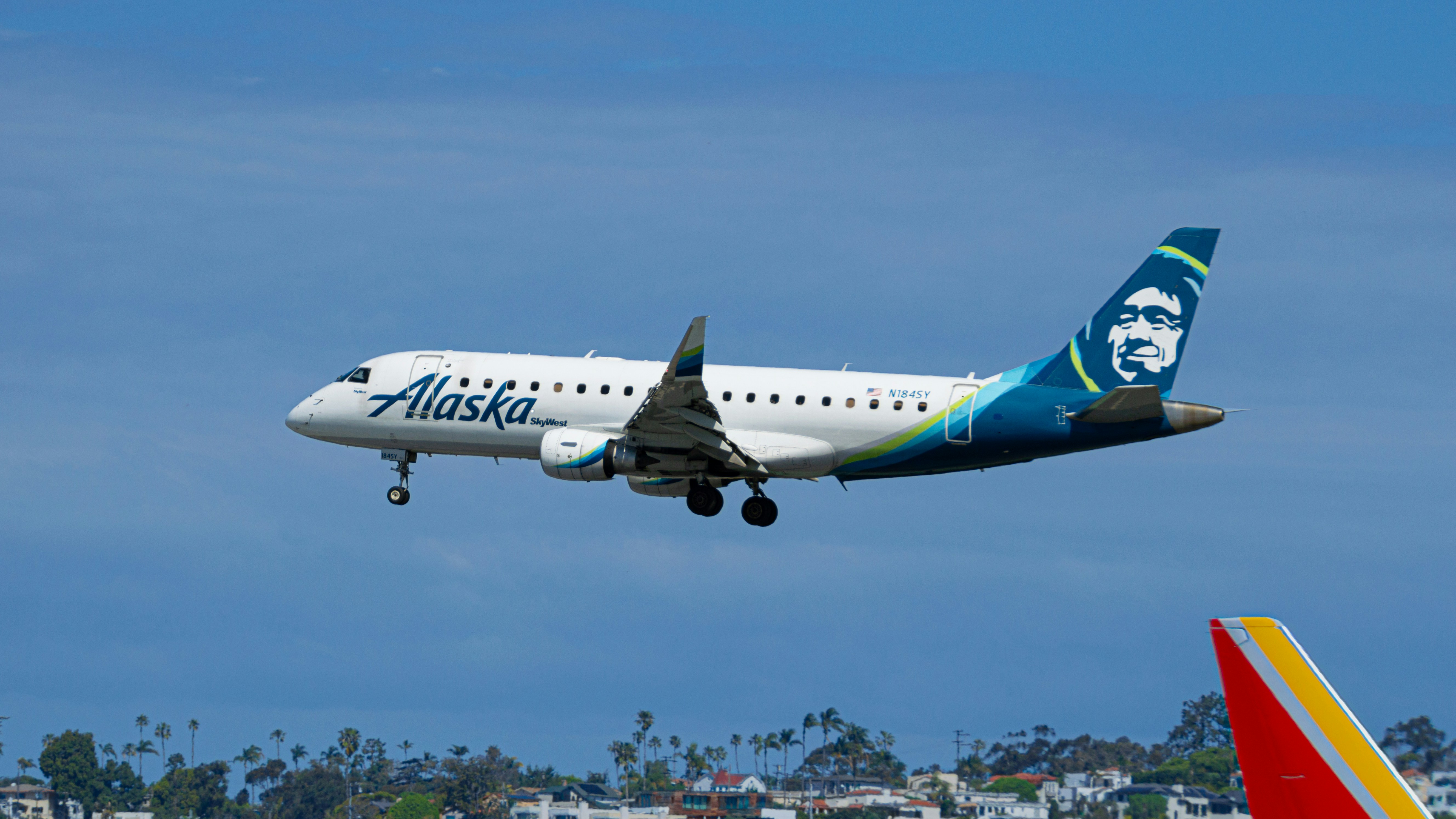 Alaska Dash: A teal-tail jet glides above a sunlit coastline