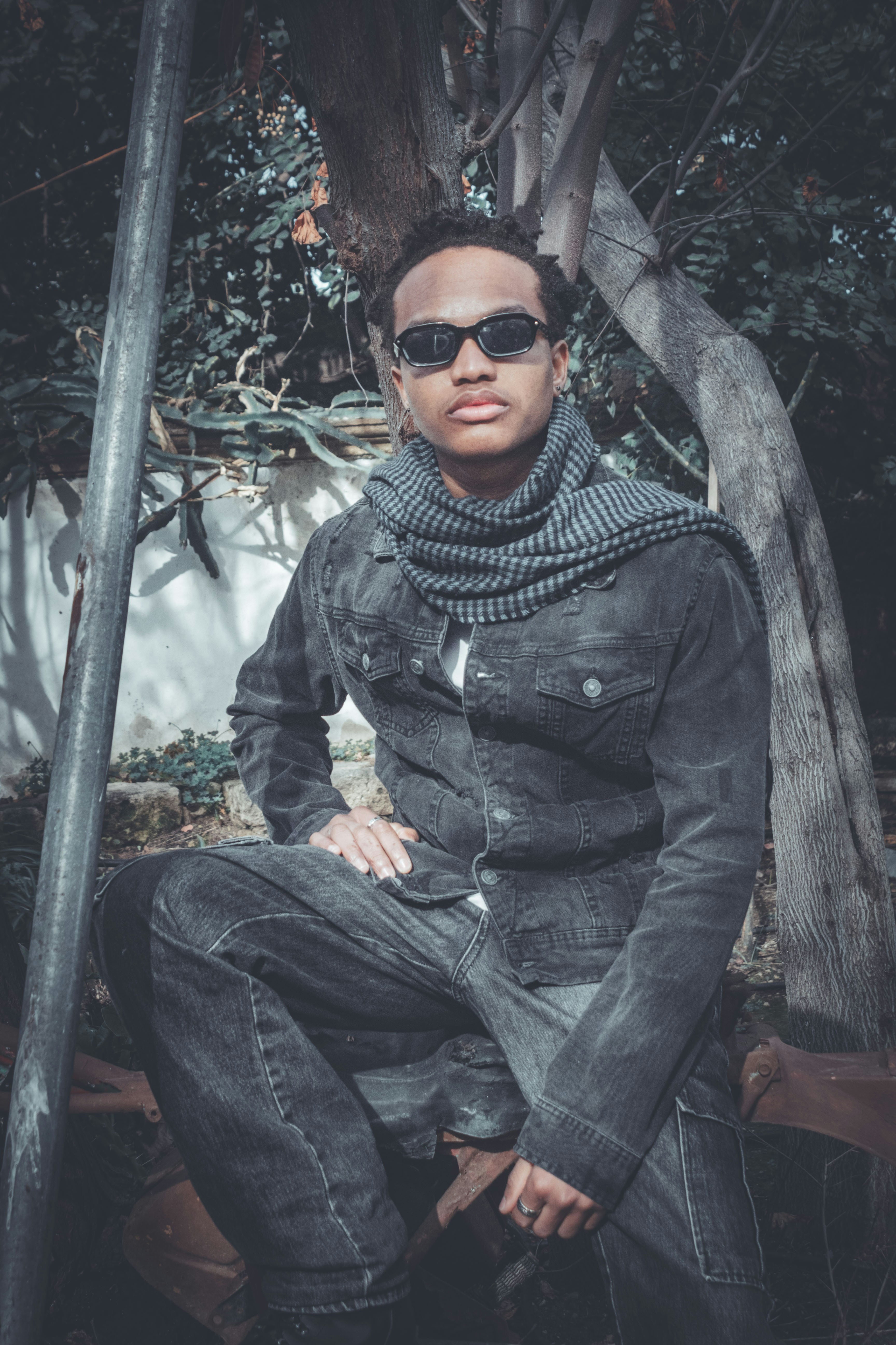 Sunglasses and Steel: A Quiet Portrait Under Verdant Branches